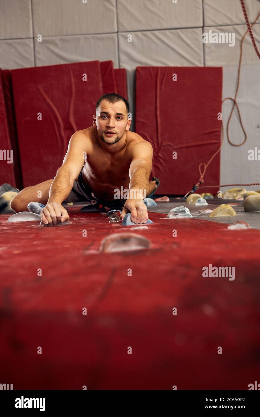 Young active man exercising at his hobby climbing on artificial red ...