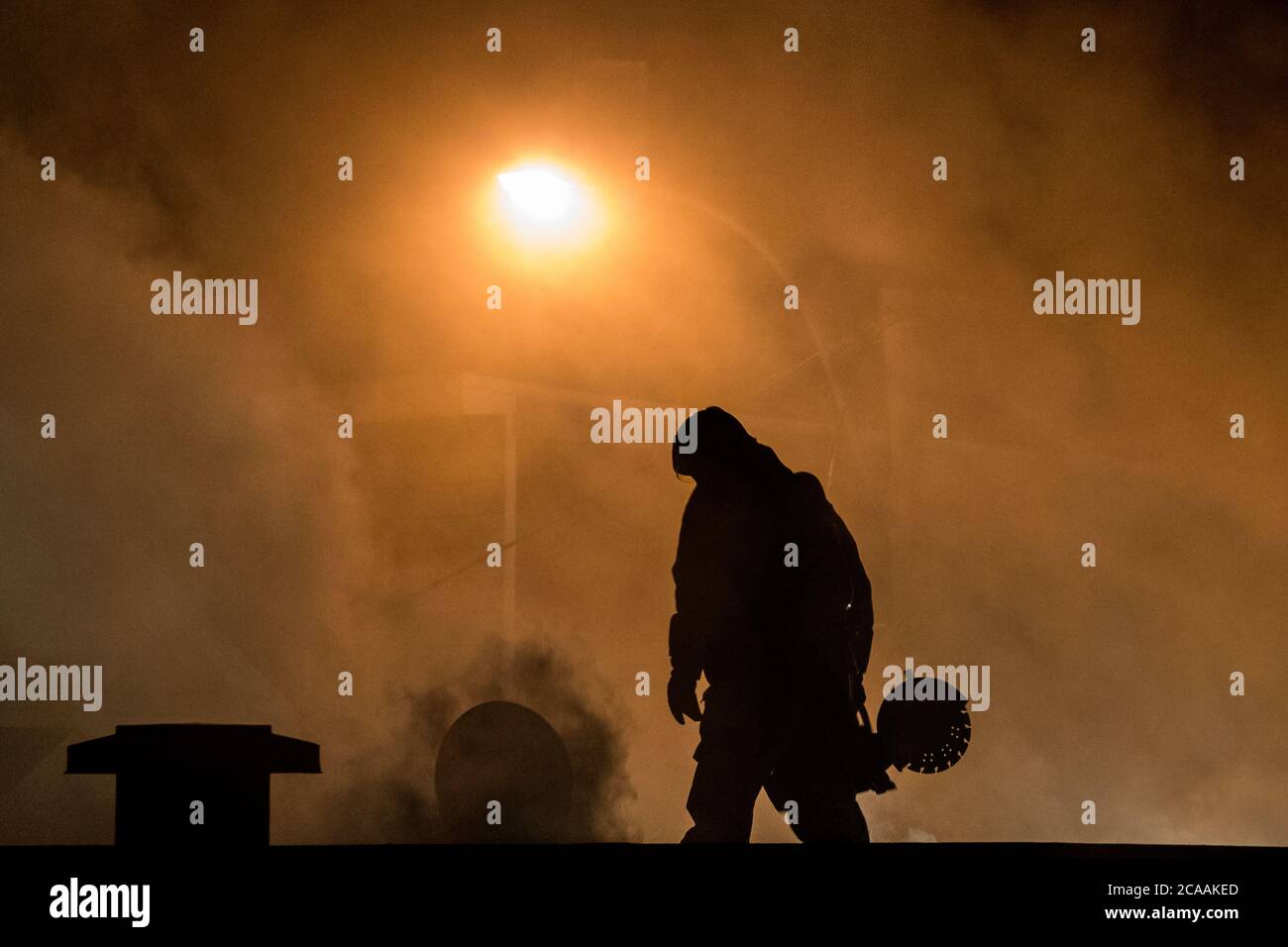 Firefighter on roof in shadow Stock Photo - Alamy