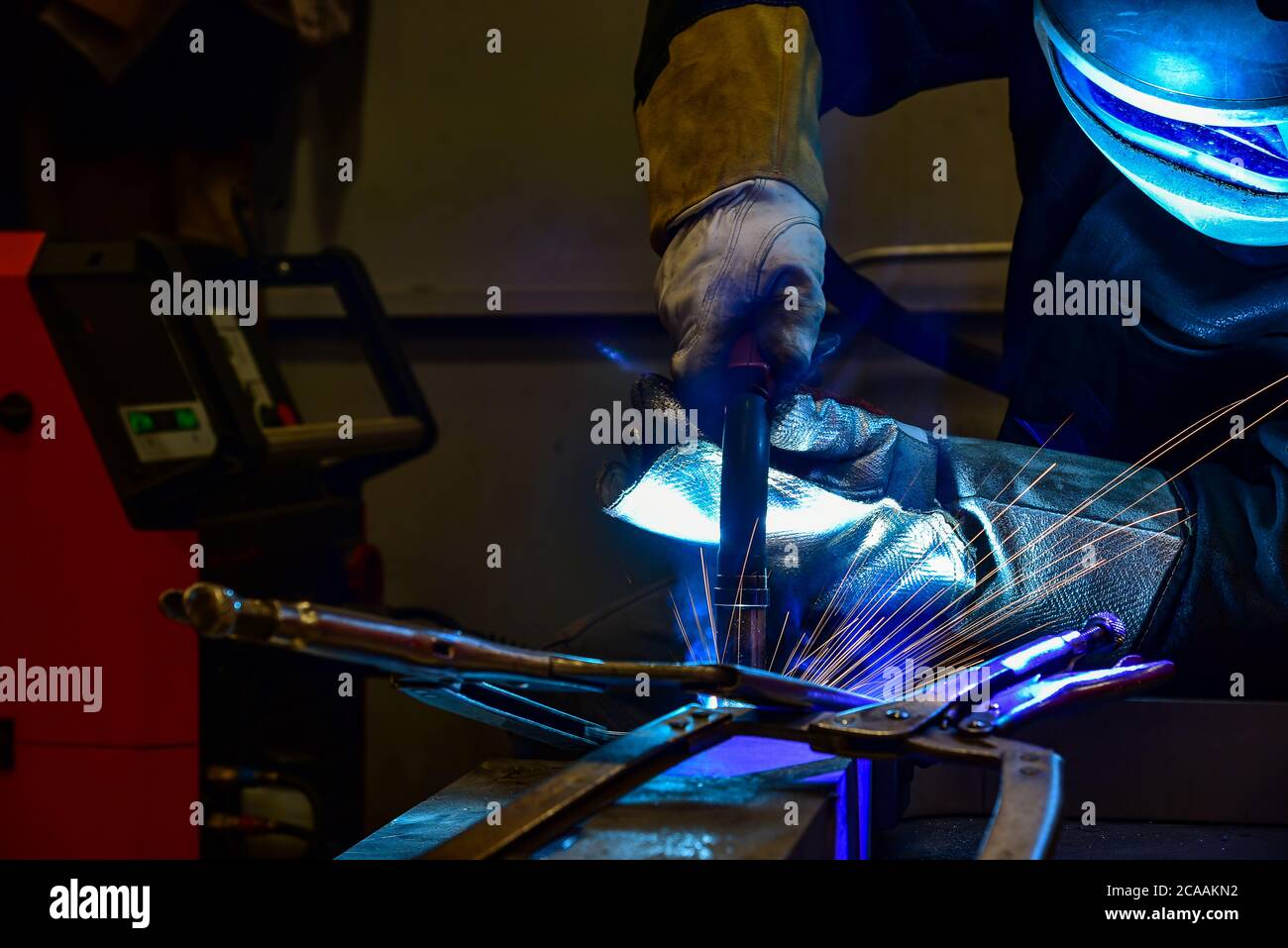 worker with protective mask welding metal and sparks. The welder is ...