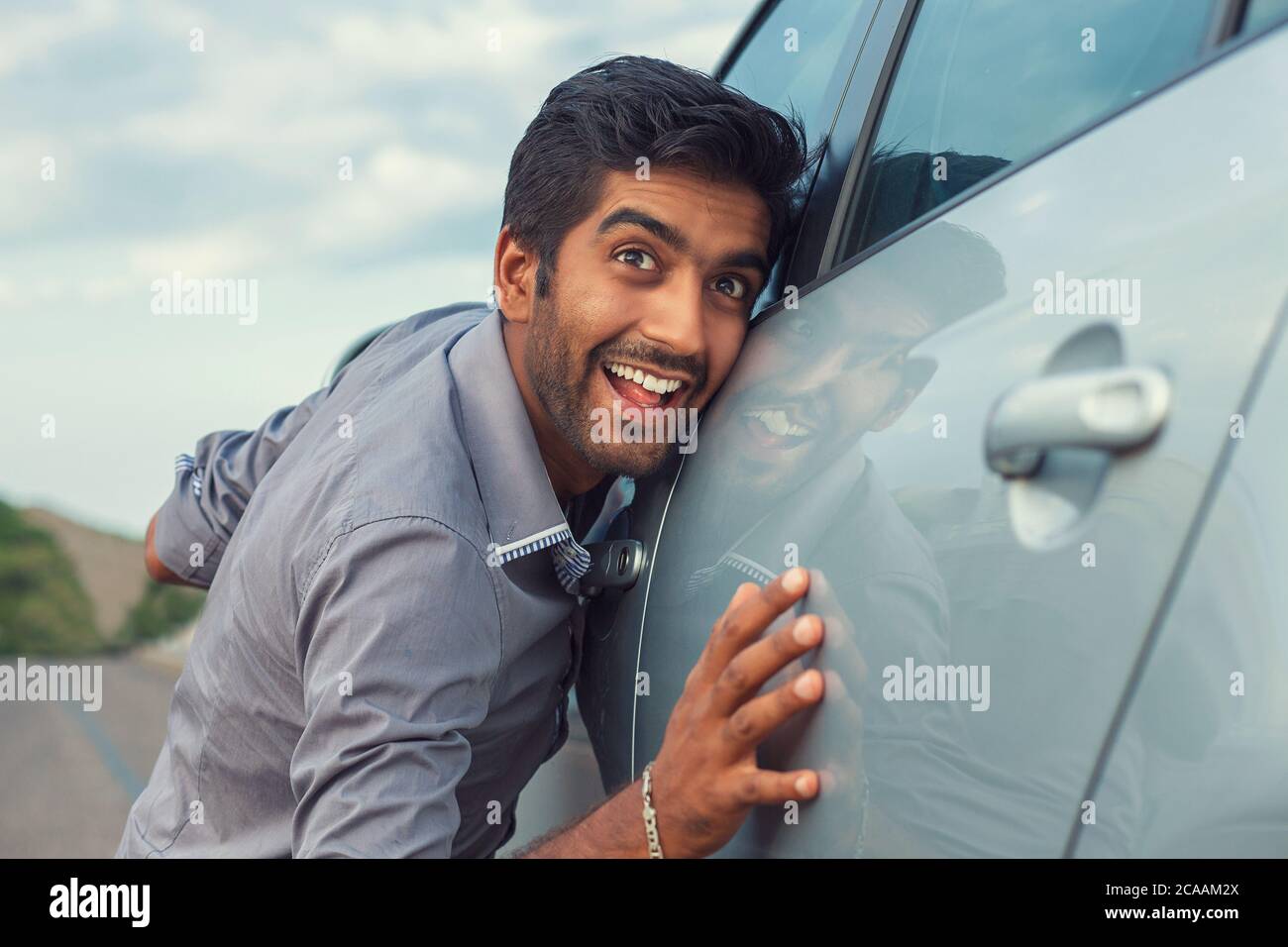 Happy Indian guy, man in formal business shirt petting his new car ...