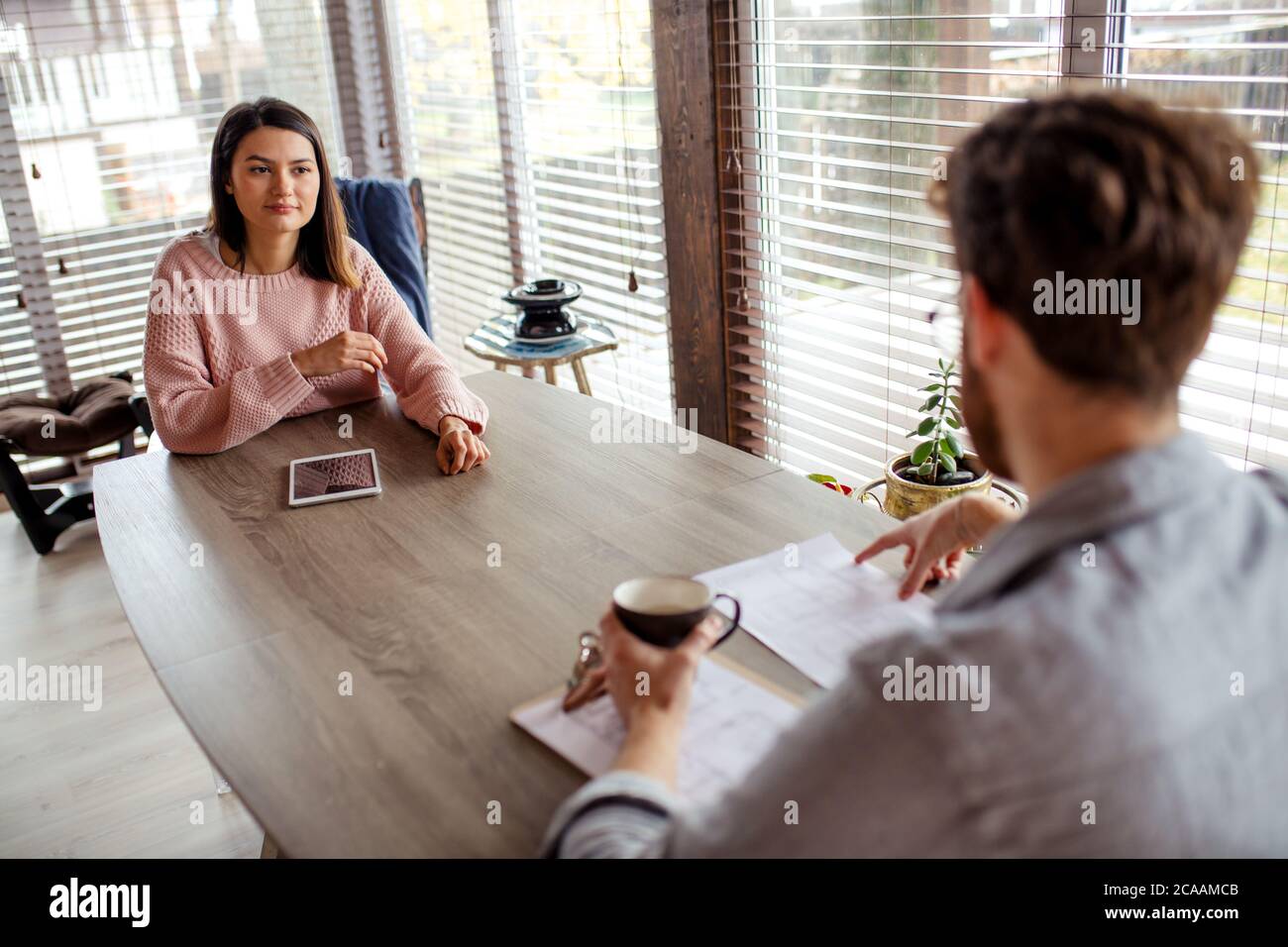 Side view of young co-workers talking at the table, woman working with ...
