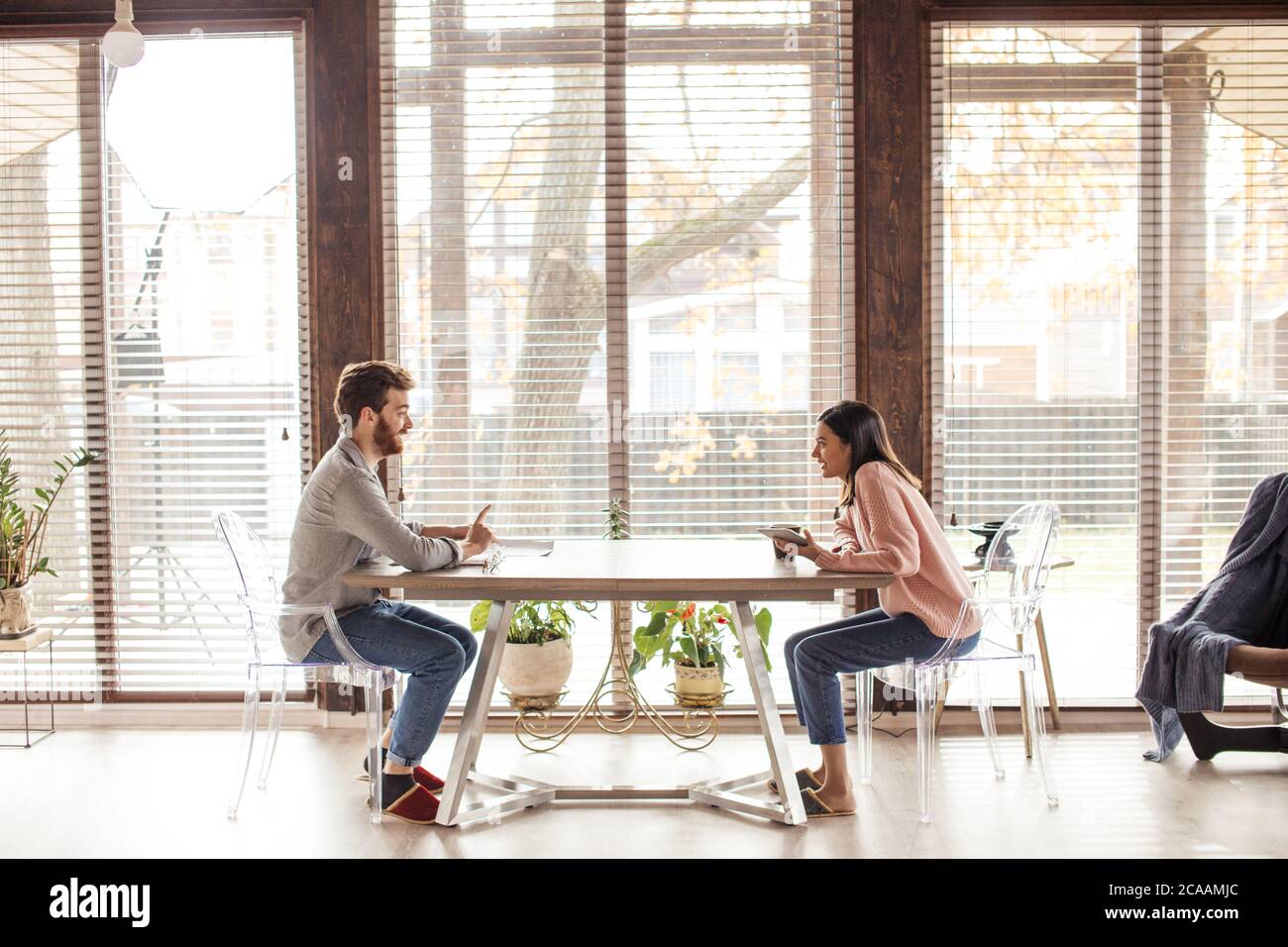 Side view of young co-workers talking at table, woman working with ...