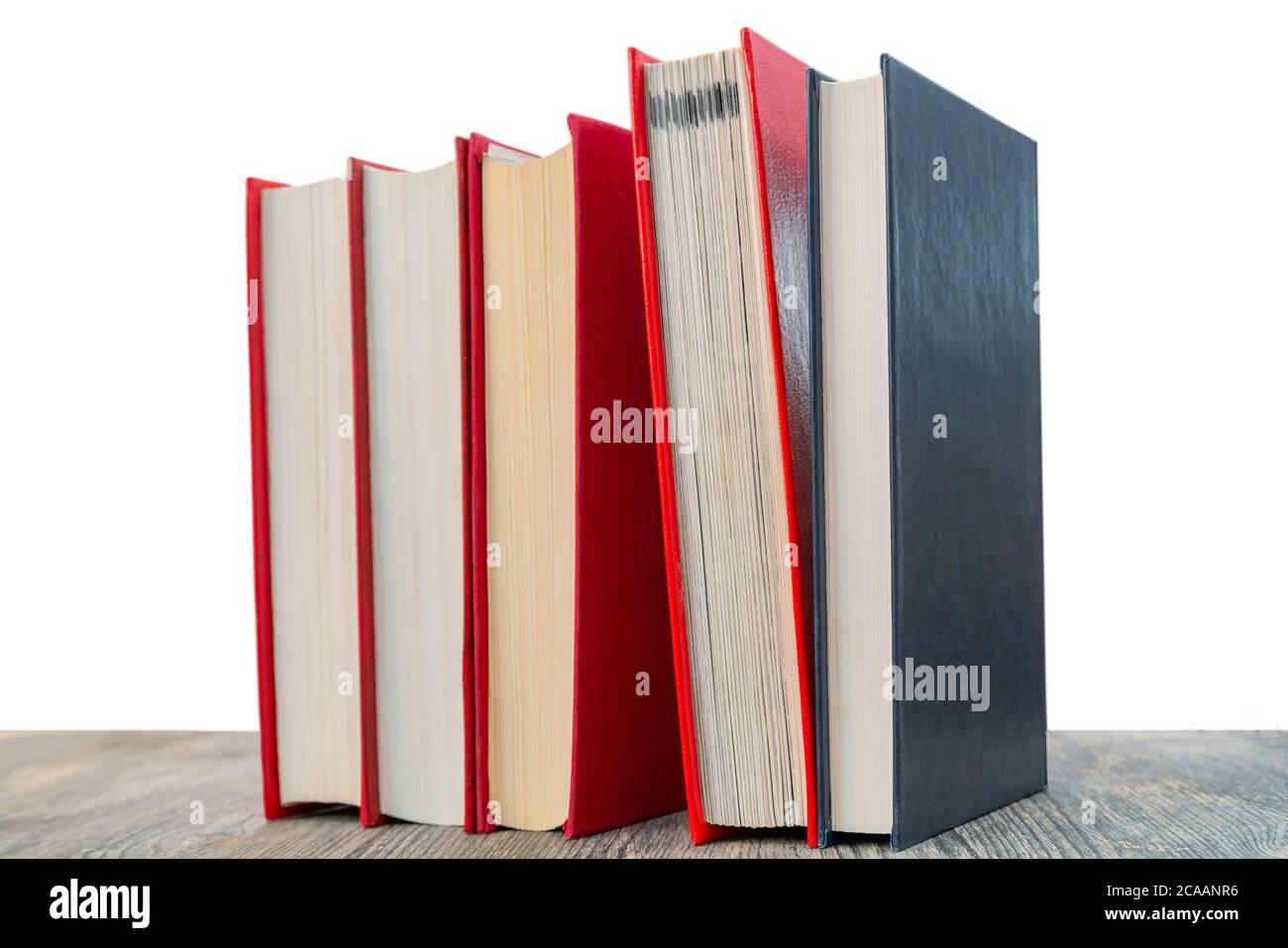 Pile of red covered books on a wooden table with a white background ...