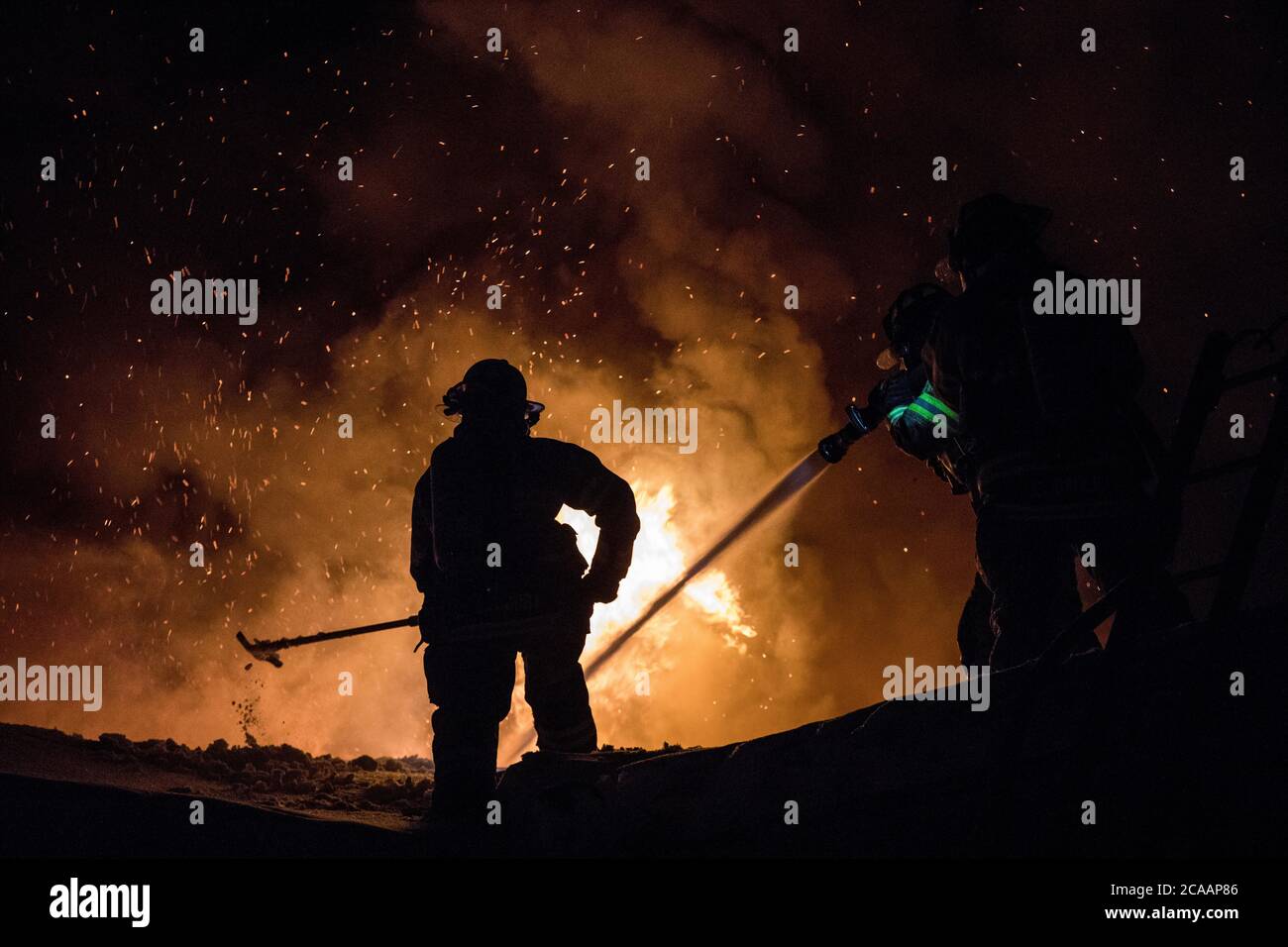 Fully engulfed house fire. Firefighter in shadow in front of fire Stock ...