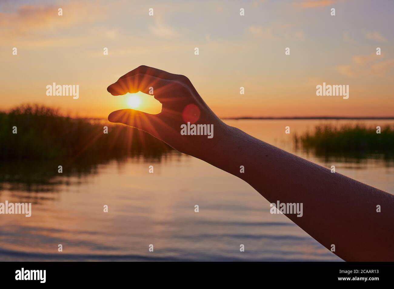 child is taking the sun in one hand, trying to catch it in front of the ...