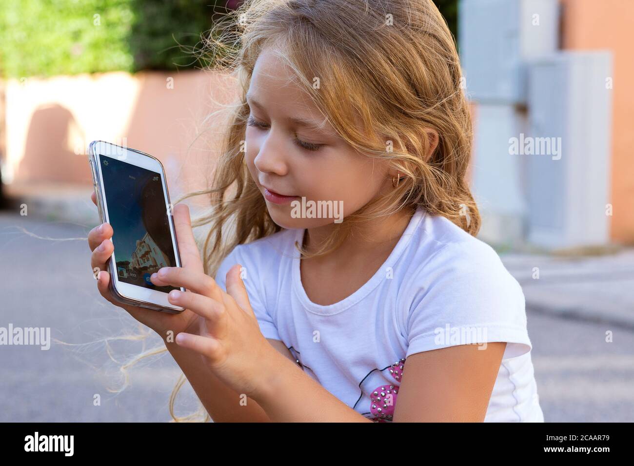 Little girl using smartphone camera and tapping on screen while ...