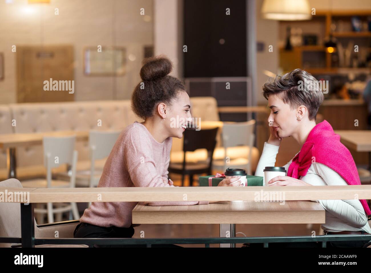 Two young female friends having coffee break together, having fun in ...