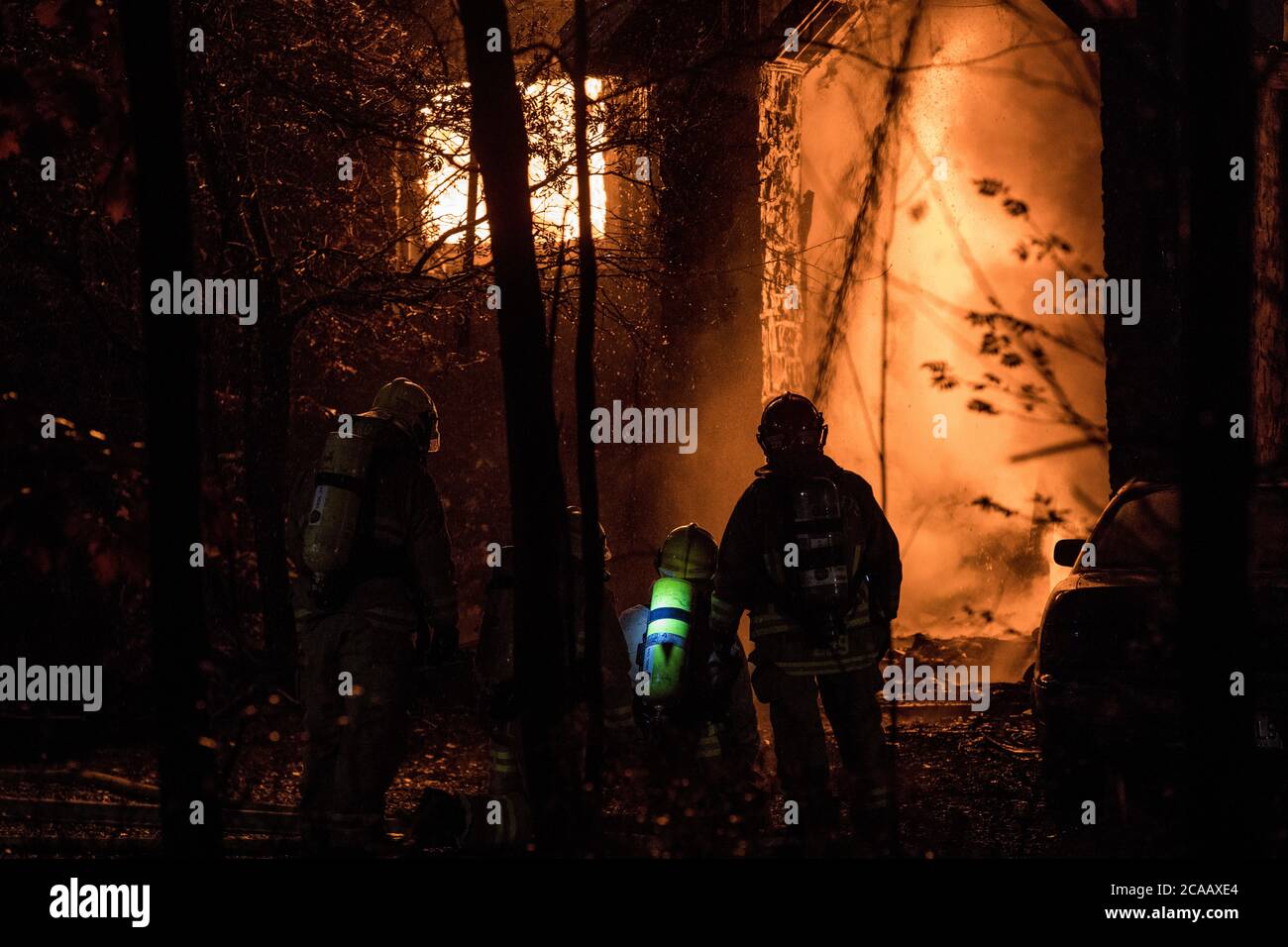 Fully engulfed house fire. Firefighter in shadow in front of fire Stock ...