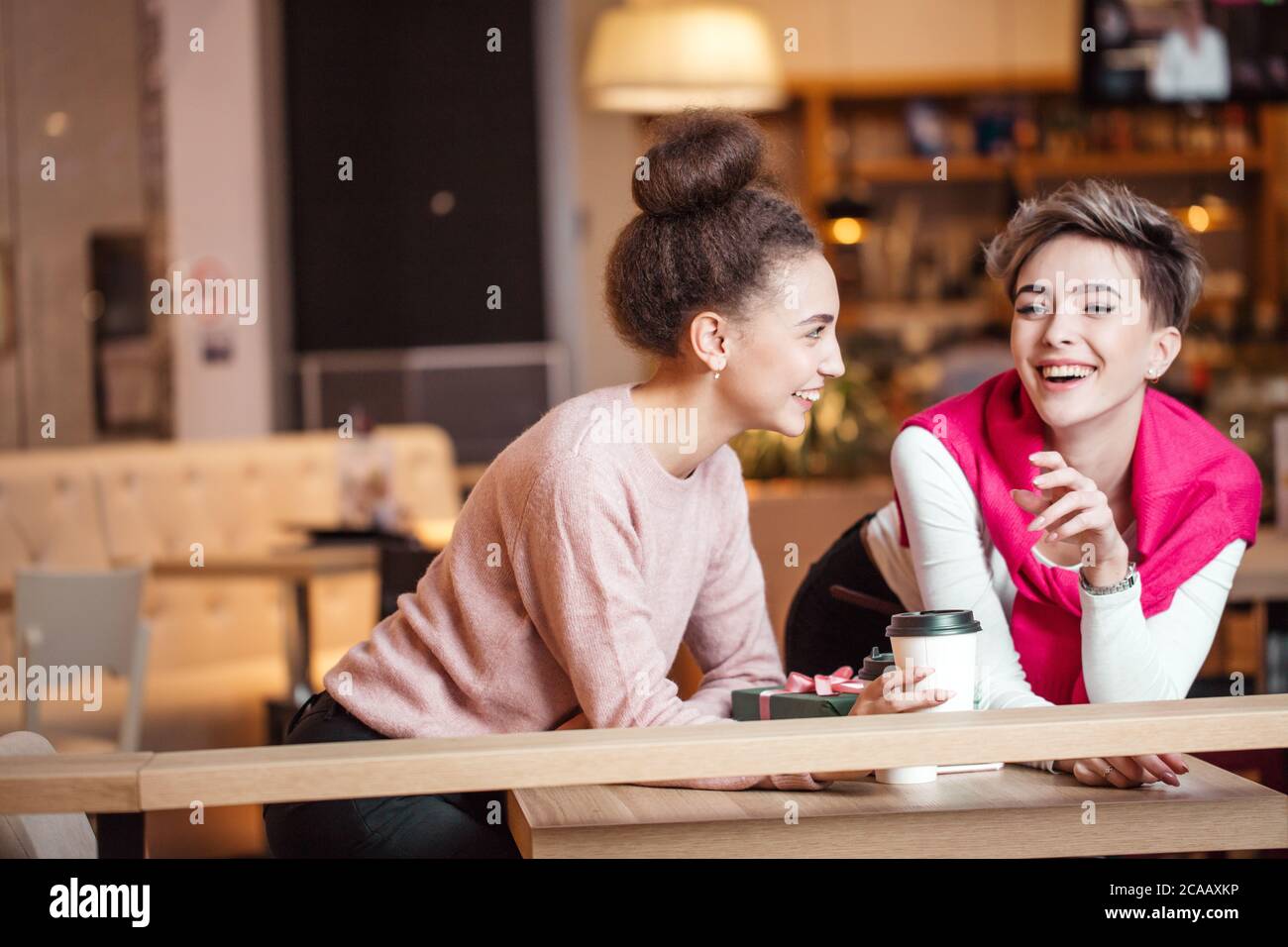 Female cheerful co-workers having lunch together at the mall ...