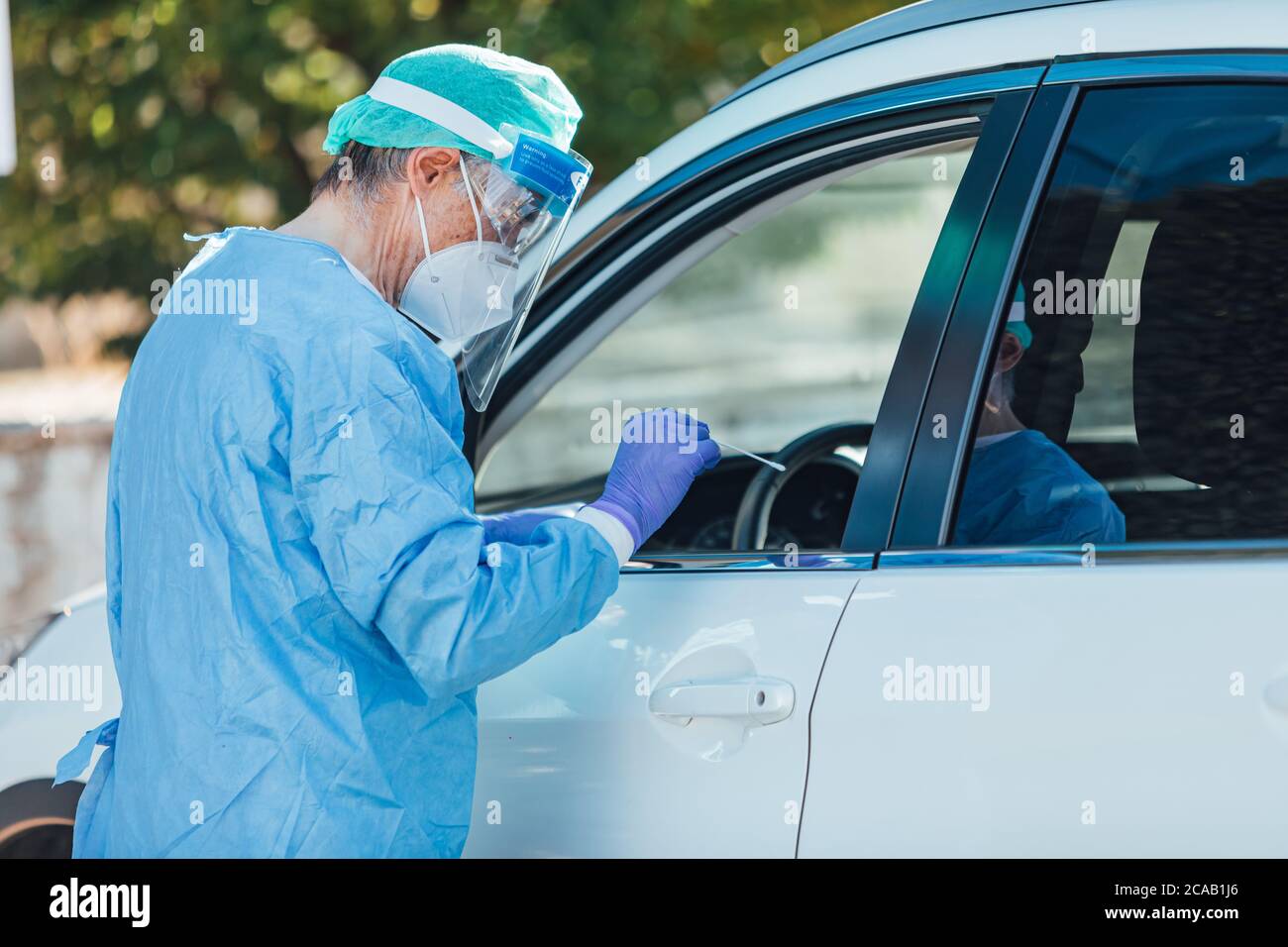 Medical personnel wearing a PPE, performing PCR with a swab in their ...