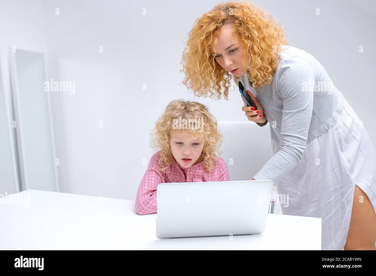 Busy Mother Helps Her Daughter To Do The Homework At Home Close Up