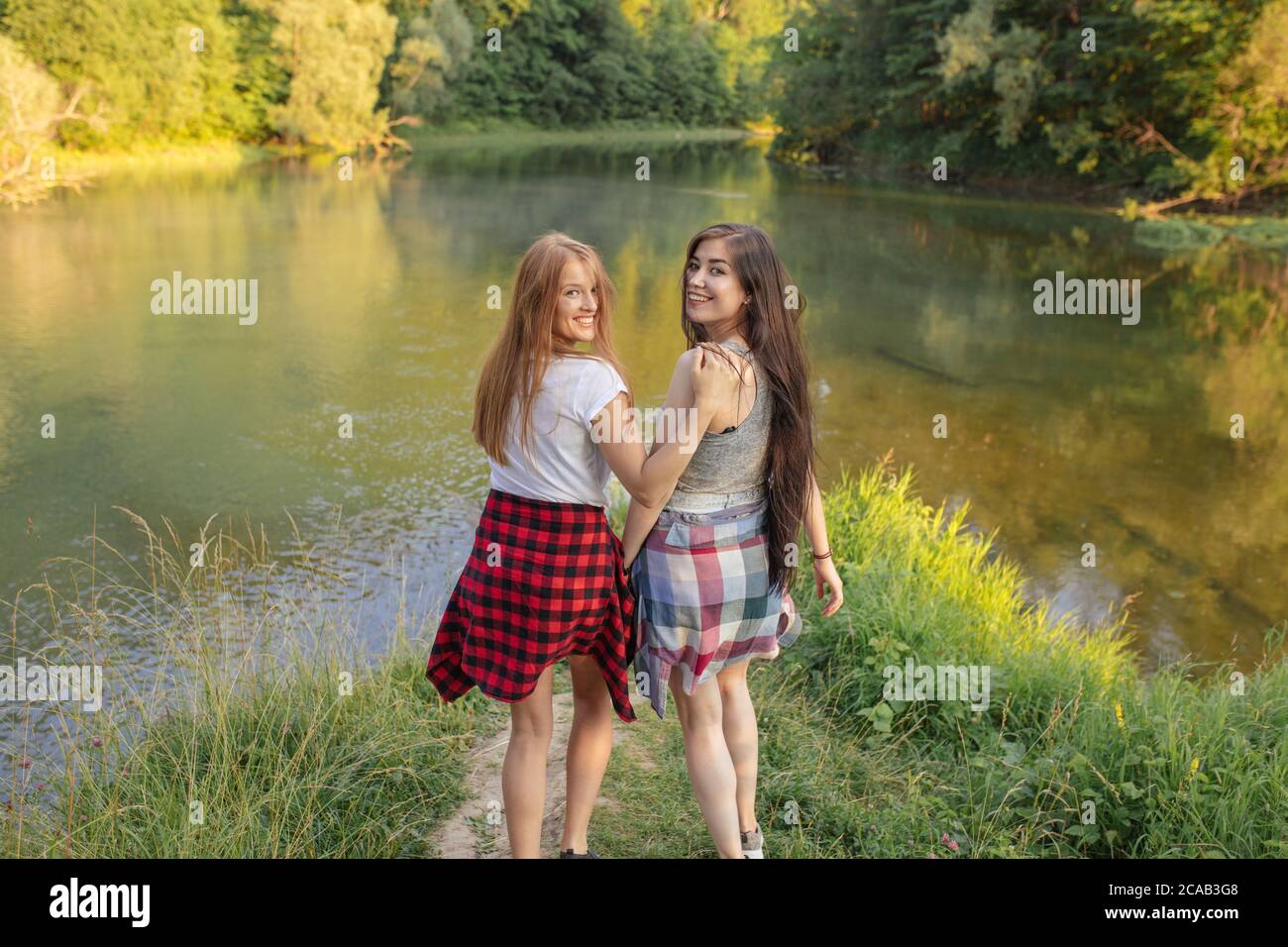 two hipster beautiful girls looking back while walking in the national ...