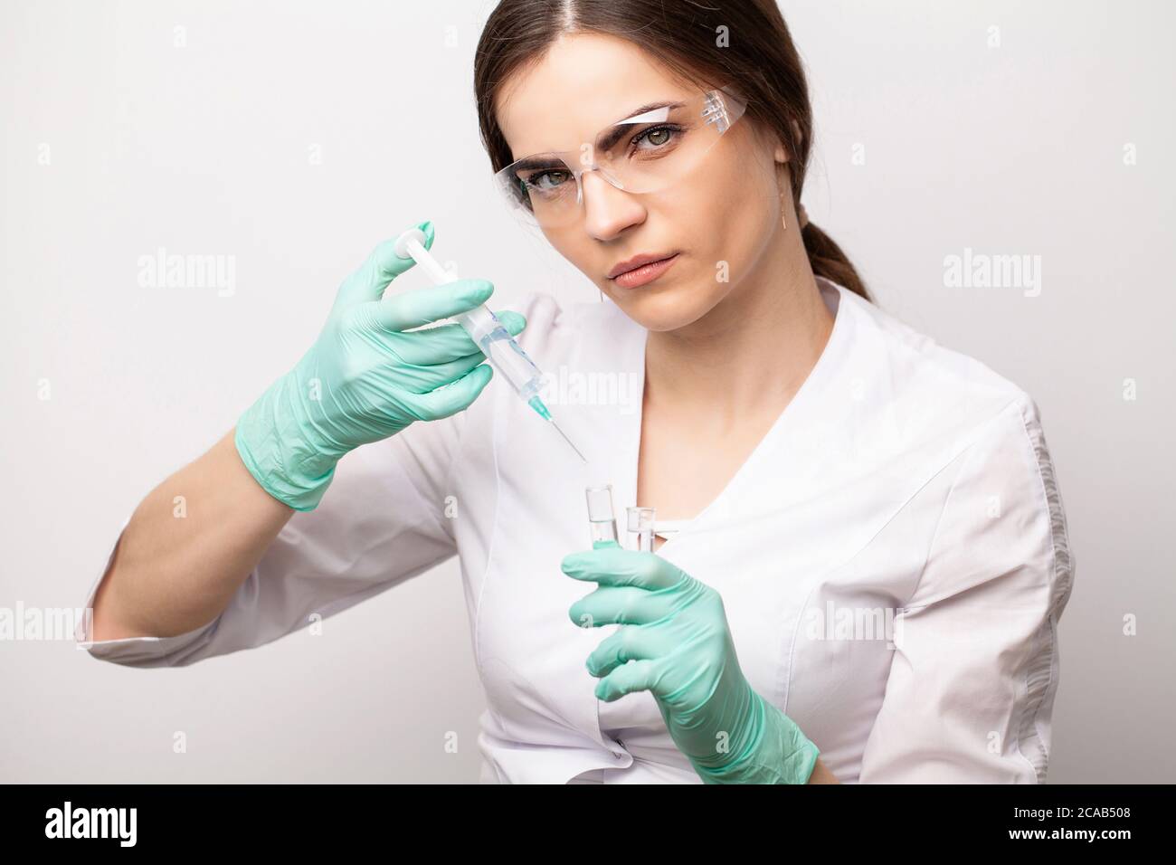 Woman doctor in medical mask picks up syringe to give an injection ...