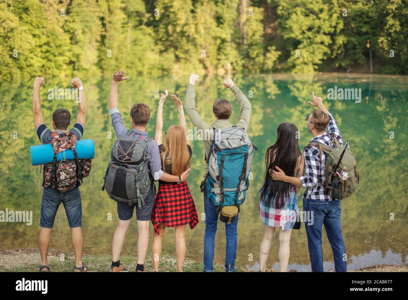 teenagers with rucksacks are arriving at the lake with beautiful nature ...