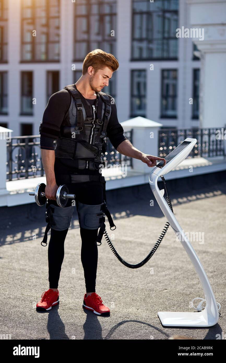 sporty awesome guy is doing electro muscular stimulation exercise. full ...