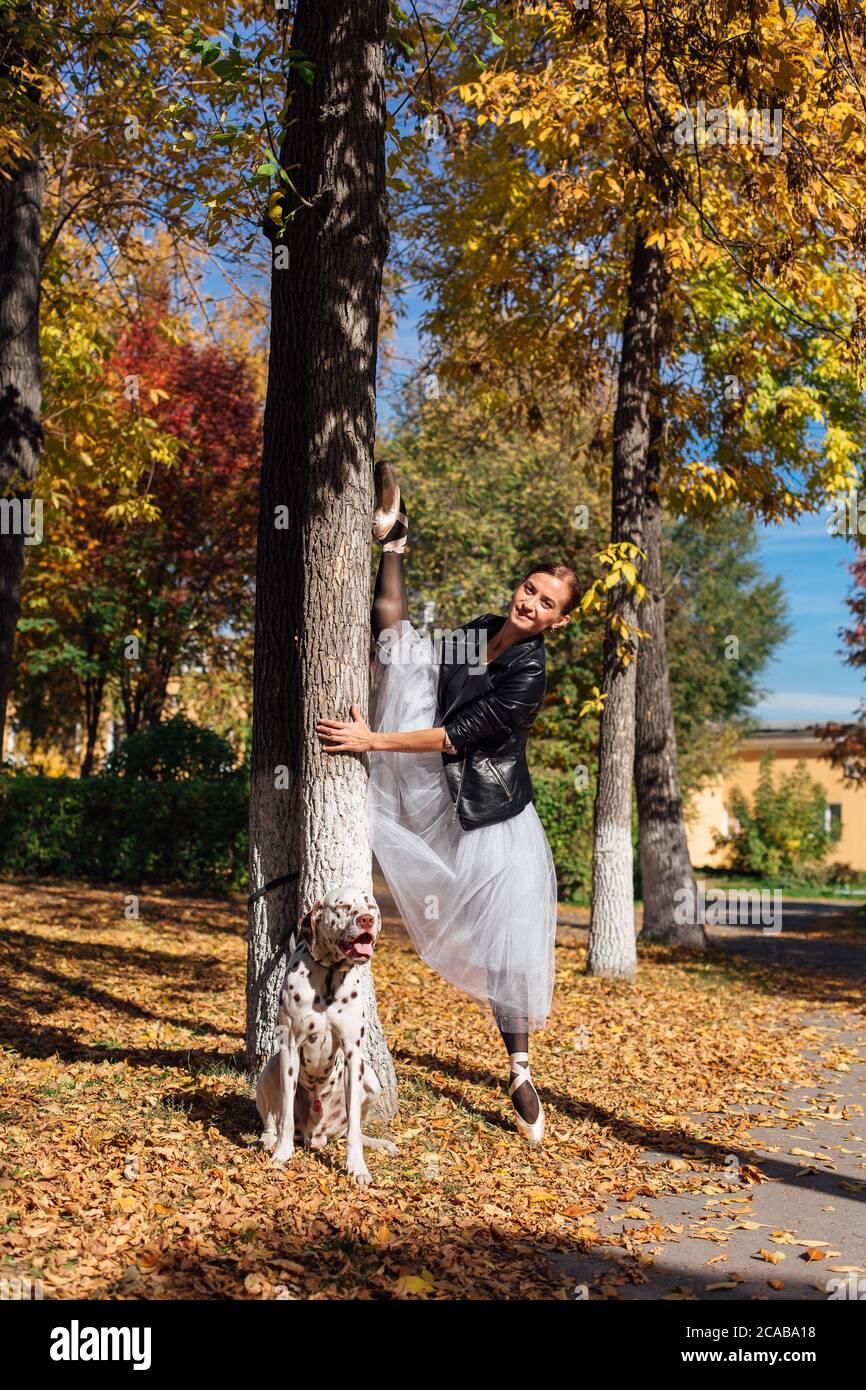 Ballerina with Dalmatian dog in the Park. Woman ballerina in a white ...