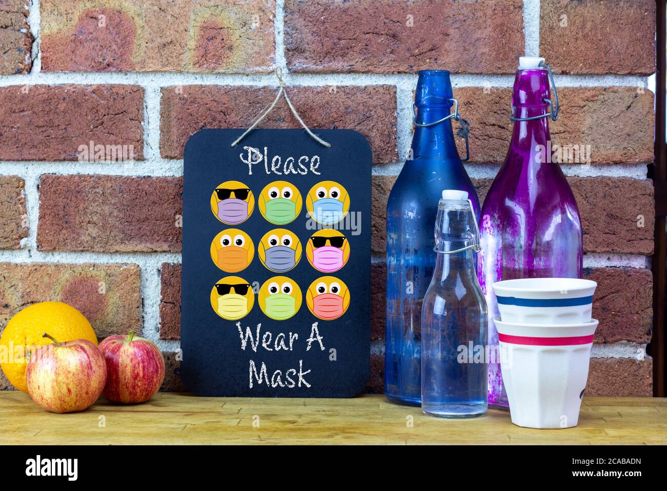 Cafe sign, please wear a mask with emoji stickers on chalk board ...