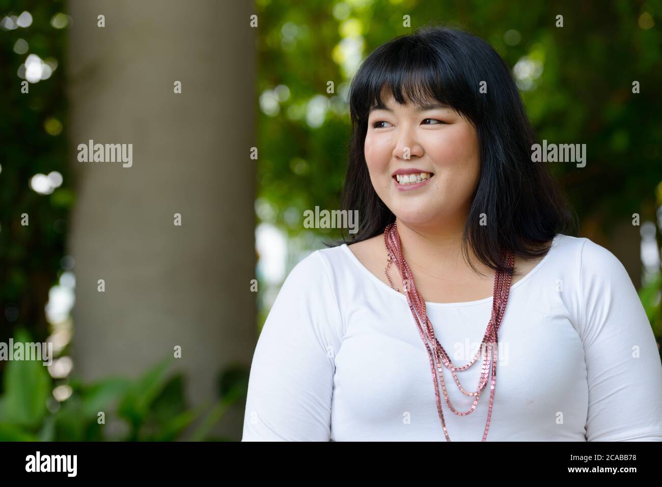 Happy young beautiful overweight Asian woman at the park Stock Photo ...