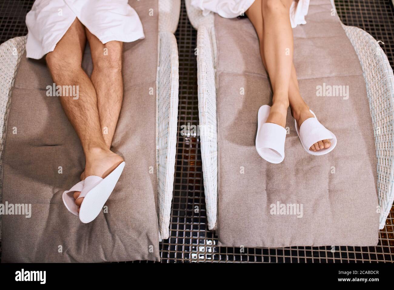 close up of long legs of clients resting on soft armchairs, keeping ...