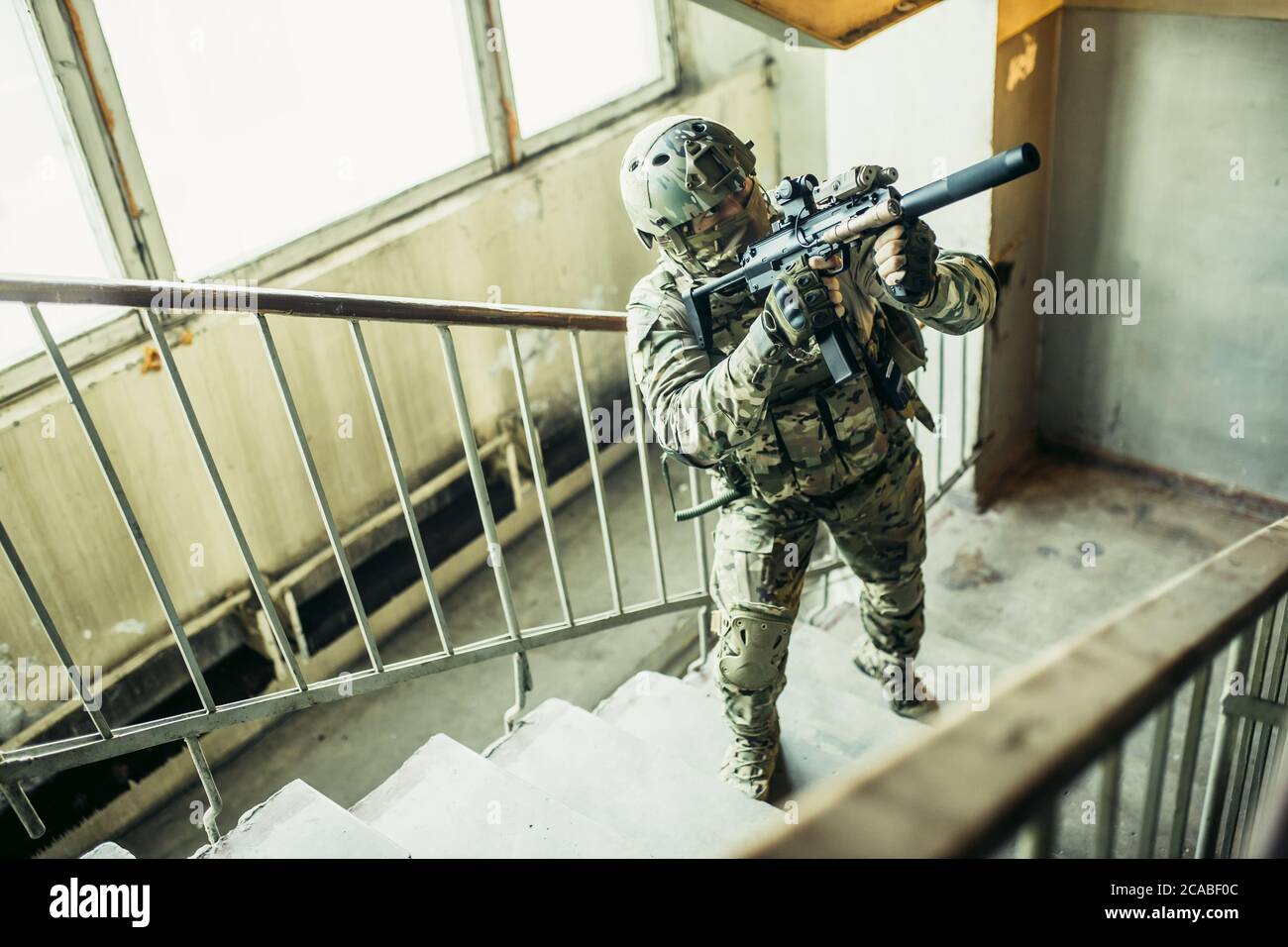 warlike soldier man goes up the stair looking for enemy or danger ...
