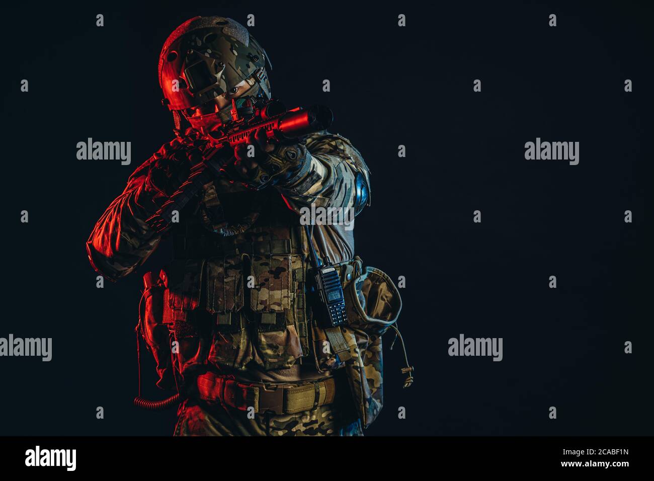 portrait of young military man pointing gun, wearing green army wear ...