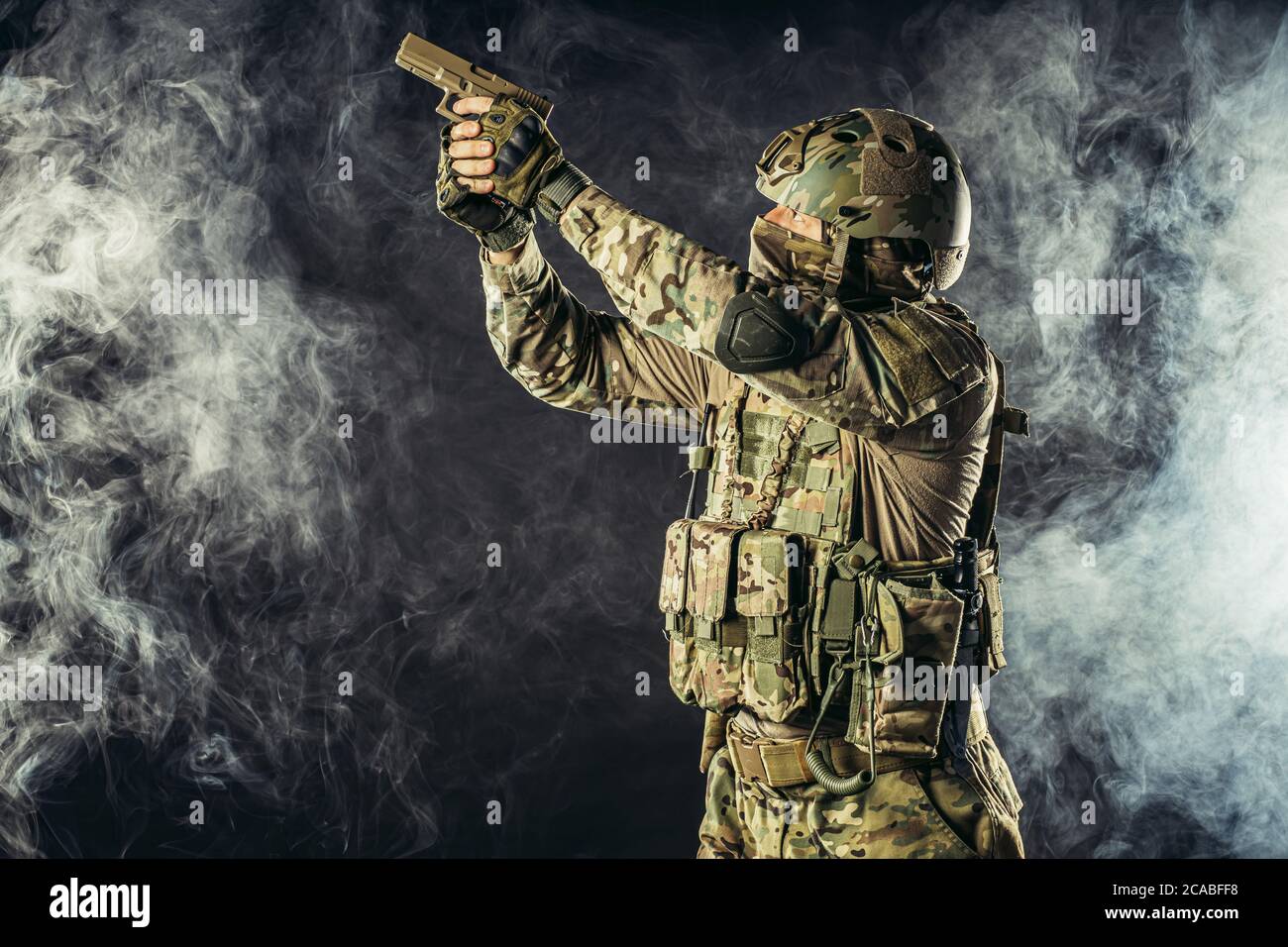 portrait of young army soldier in action with gun, dark and foggy ...