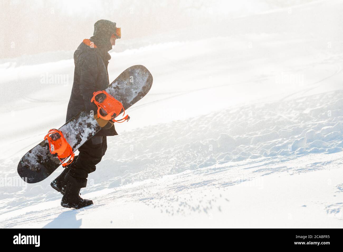 pensive guy is walking with a snowboard on a hill. copy space ...
