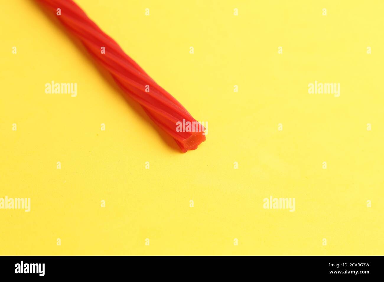Red gummy licorice on isolated yellow background Stock Photo - Alamy