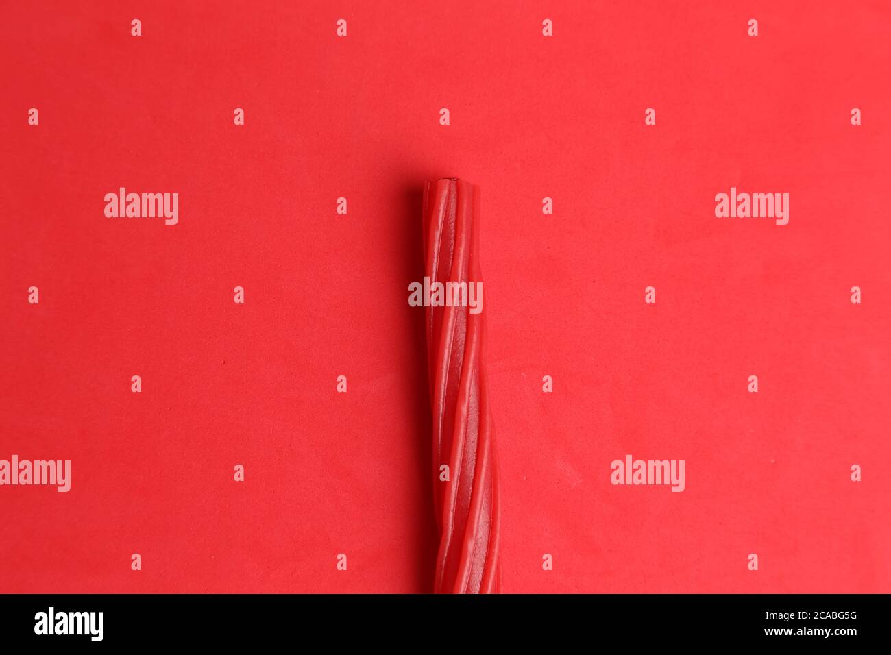 Top view of a single piece of red licorice on a red background Stock ...