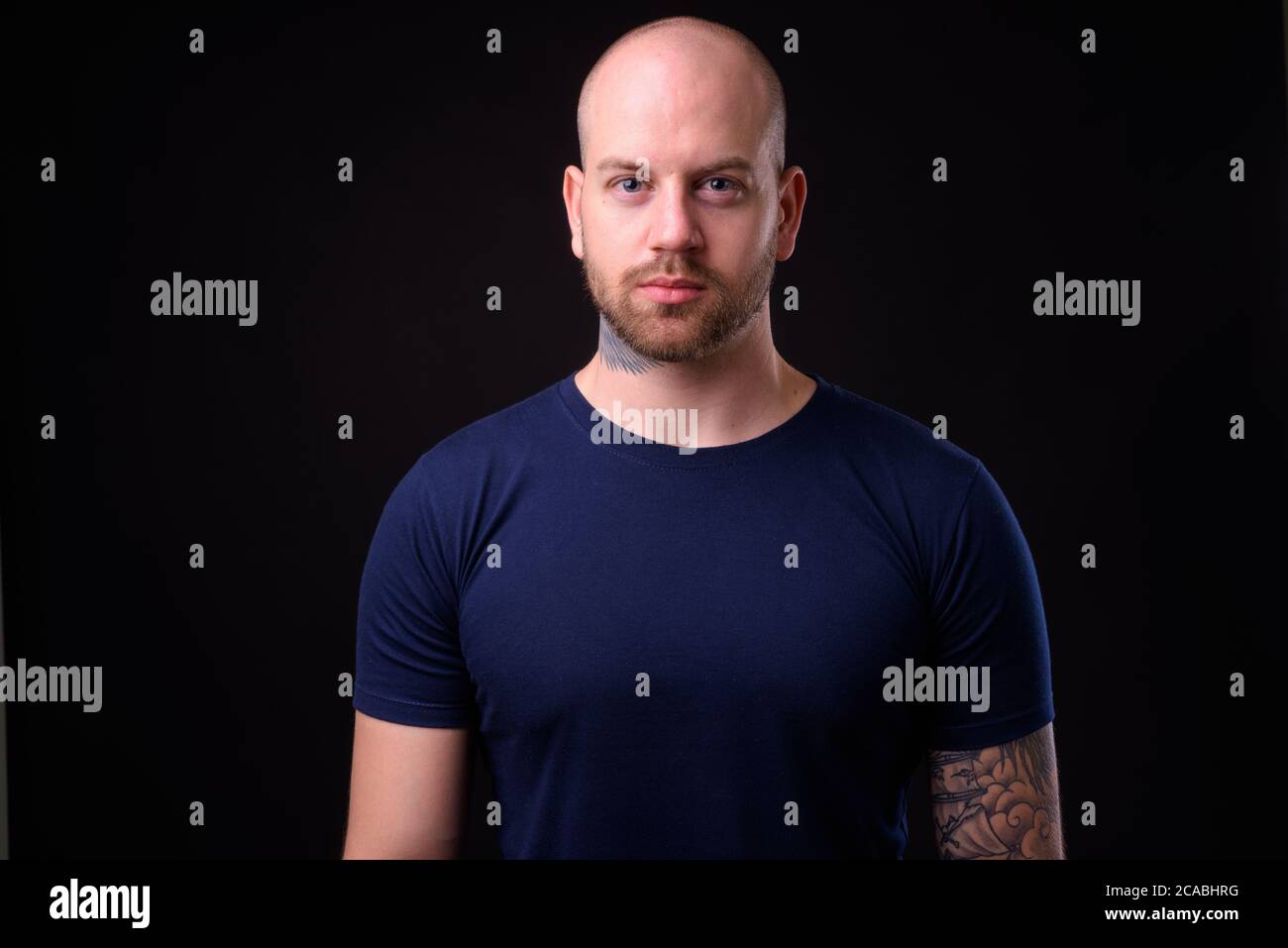 Handsome bald bearded man against black background Stock Photo - Alamy