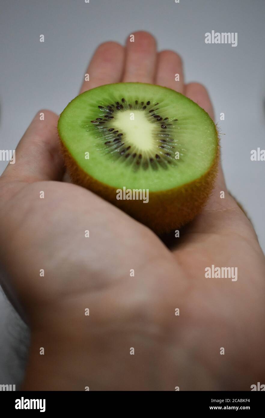 Vertical shot of a half-cut kiwi in a hand Stock Photo - Alamy
