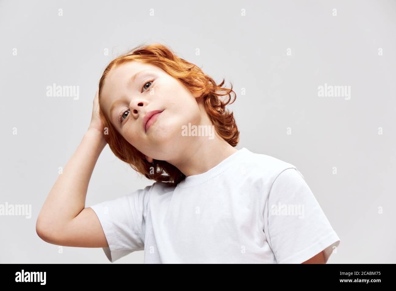 Cute redhead boy holding his hand on his head white t-shirt cropped ...