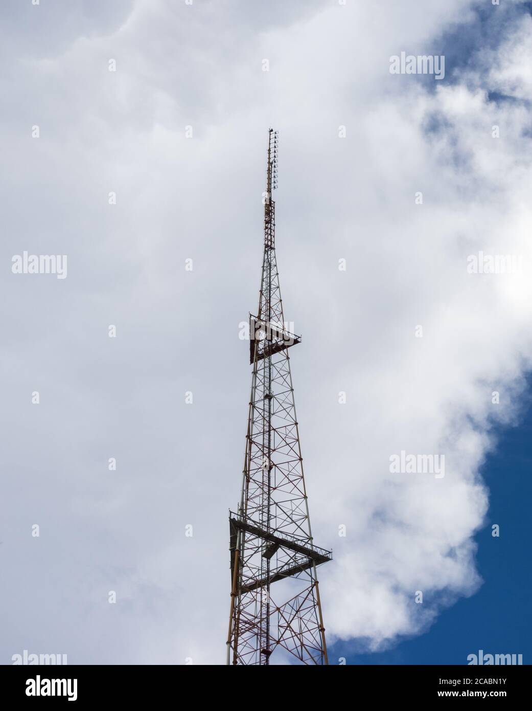 Vertical shot of a tall telephone tower with a cloudy sky background ...