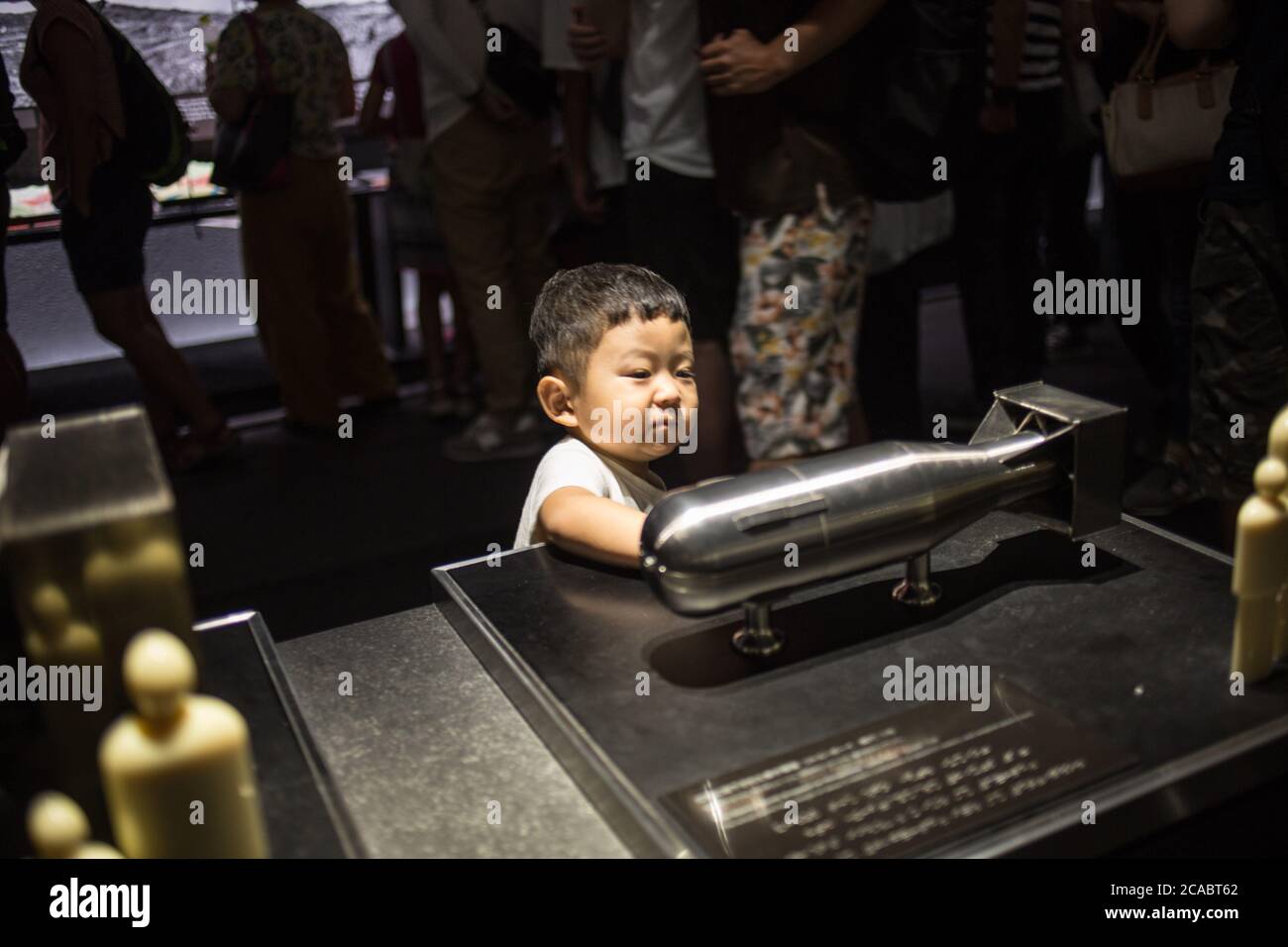 A little boy is touching a miniature scale model of the atomib bomb ...
