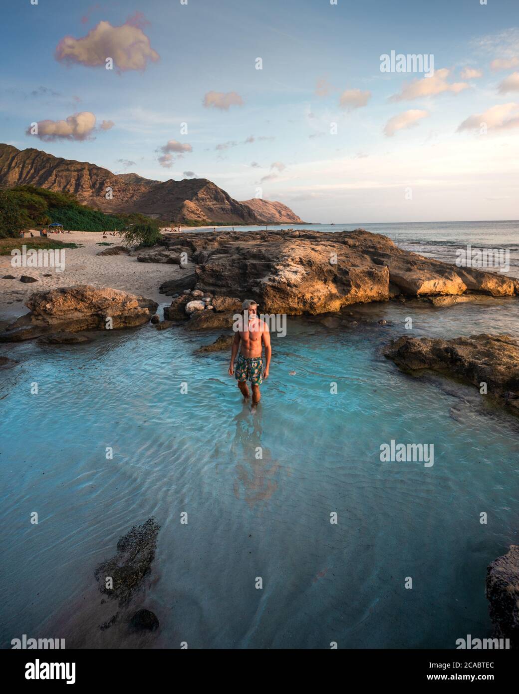Male model standing in the water on background of rocks and boundless ...
