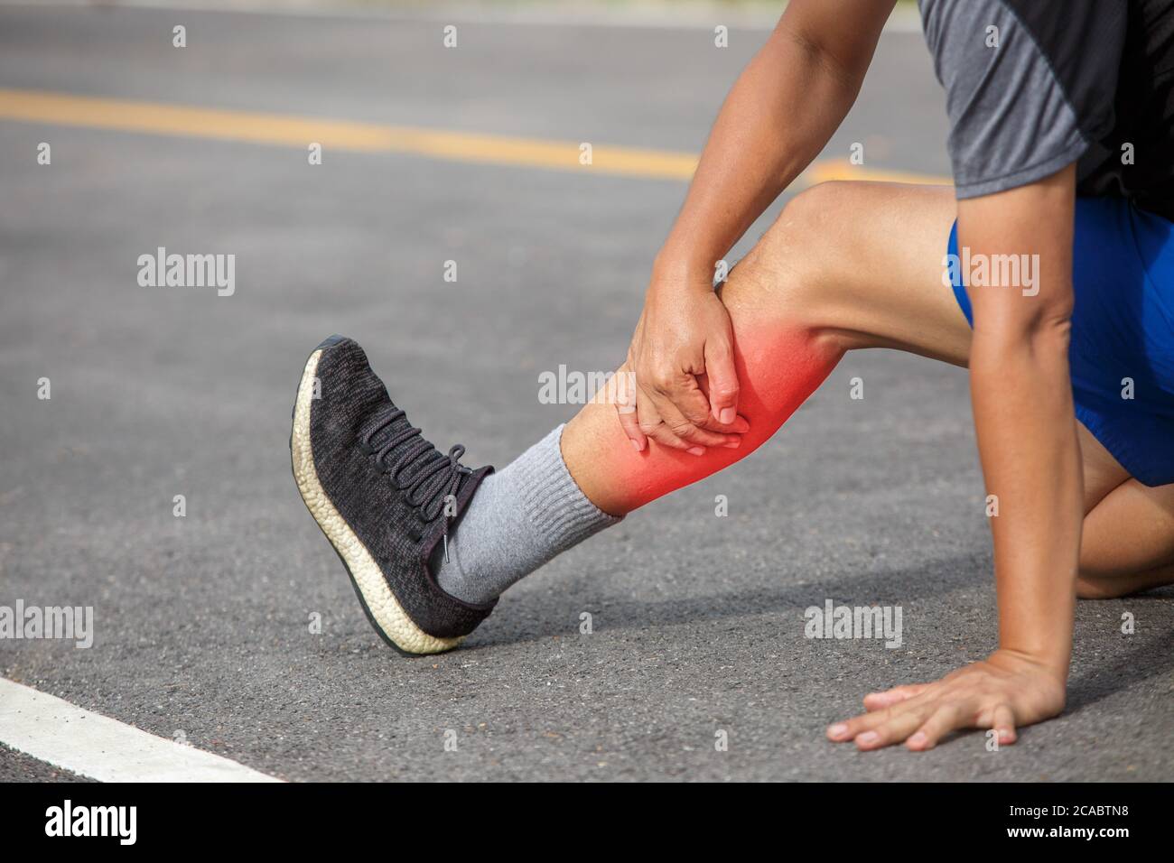 Male middle aged having a cramp while jogging. Stop and massage calf ...