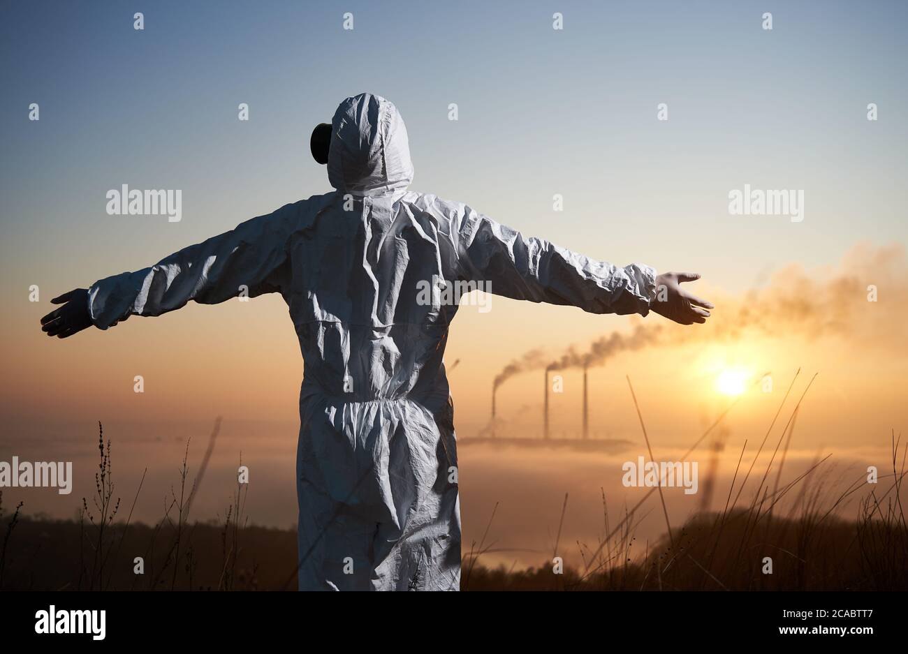 Back view of scientist in protective suit looking at blue sky over ...