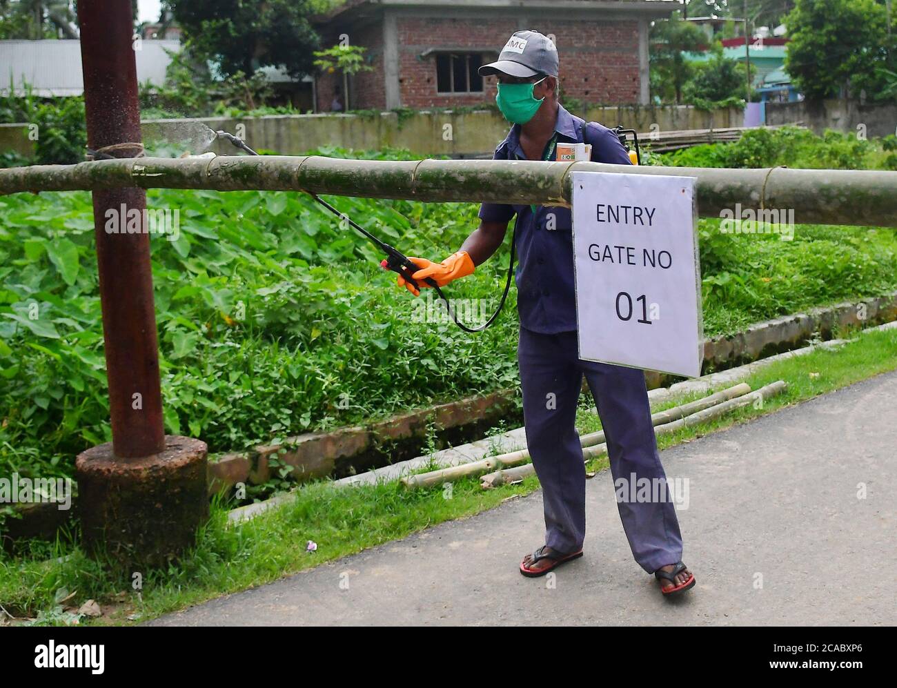 Workers wearing mask and protective gear are spraying disinfectant to ...