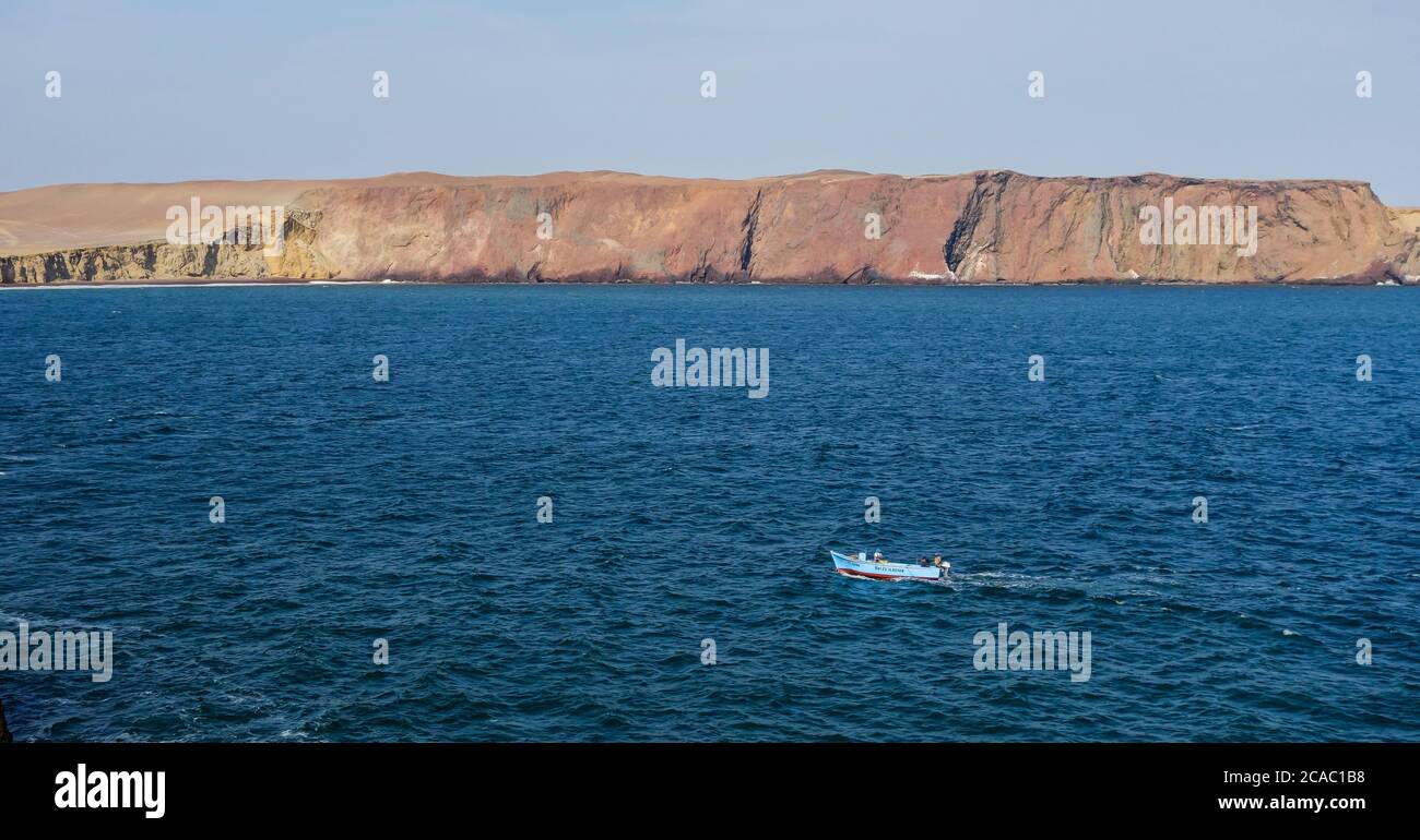 Blue ocean with a boat and the coastal cliffs at the Paracas National ...