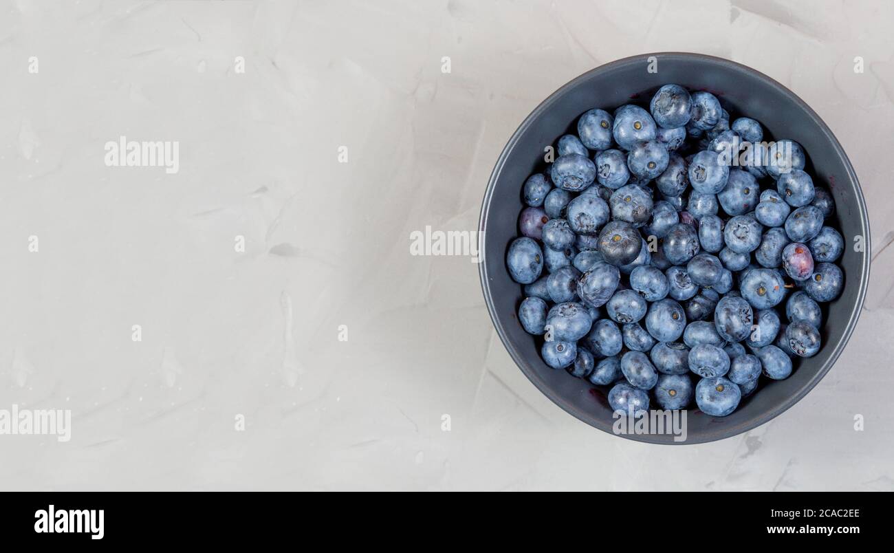 blueberry berry in dark gray ceramic bowl on gray concrete background ...