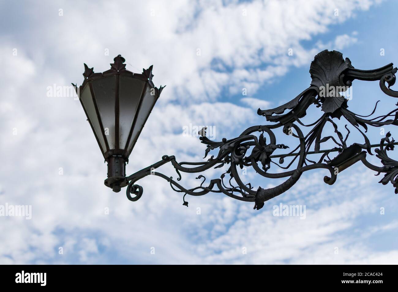 old black ornamental lamp with a cloudy background photographed midday ...