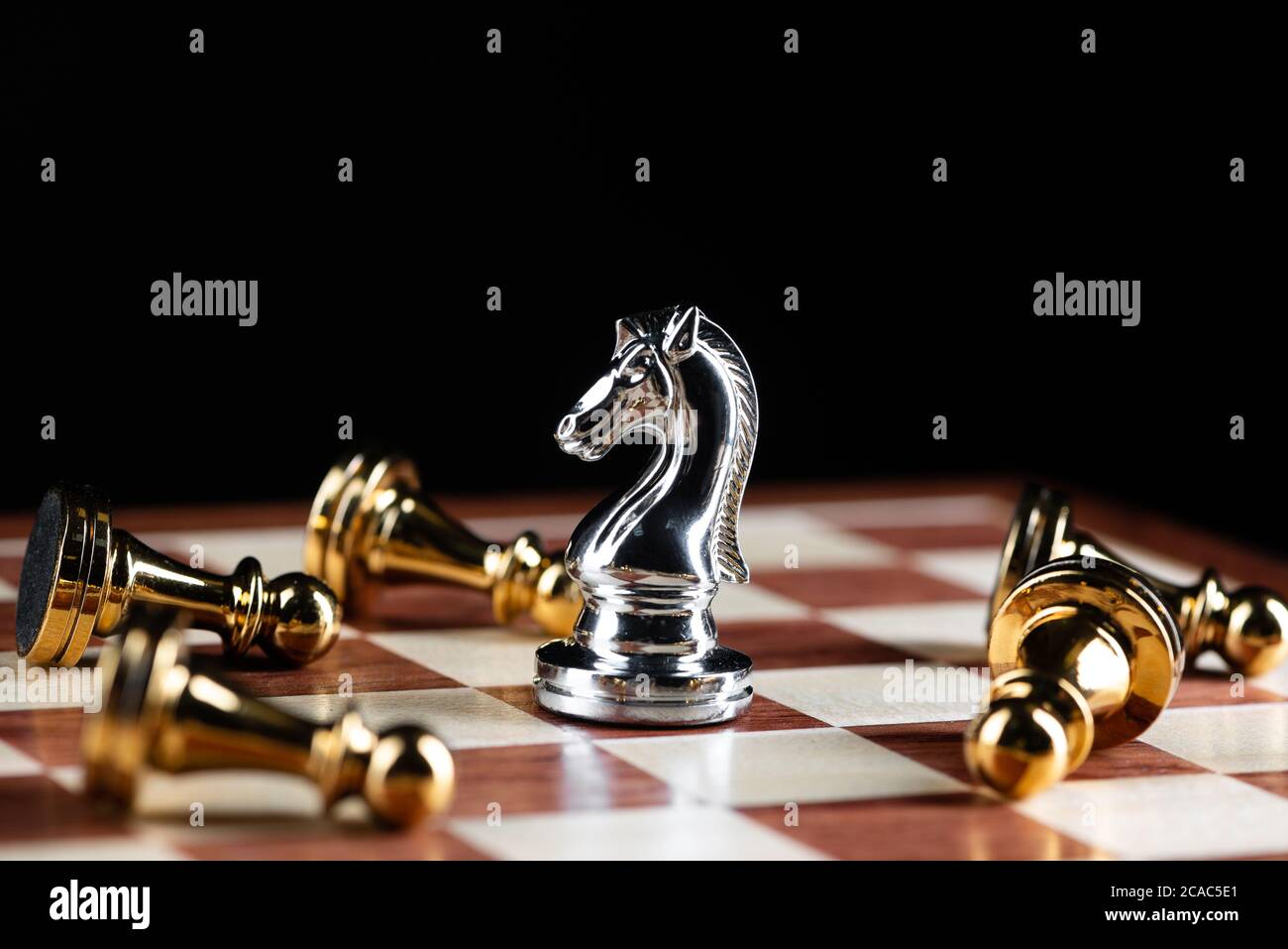 Silver knight chess defeats gold pawns on board Stock Photo - Alamy