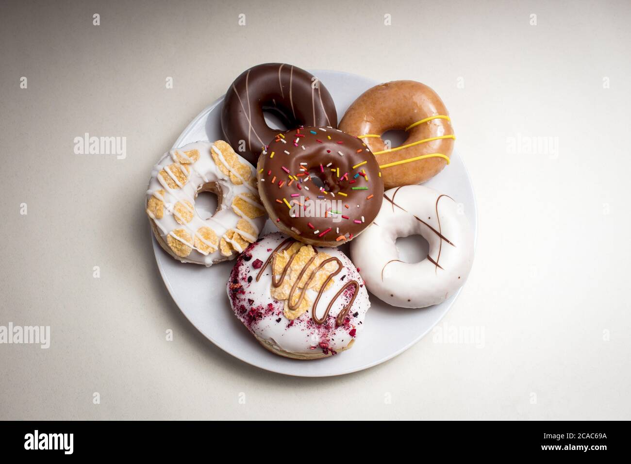 Overhead shot of different types of tasty donuts on a white background ...