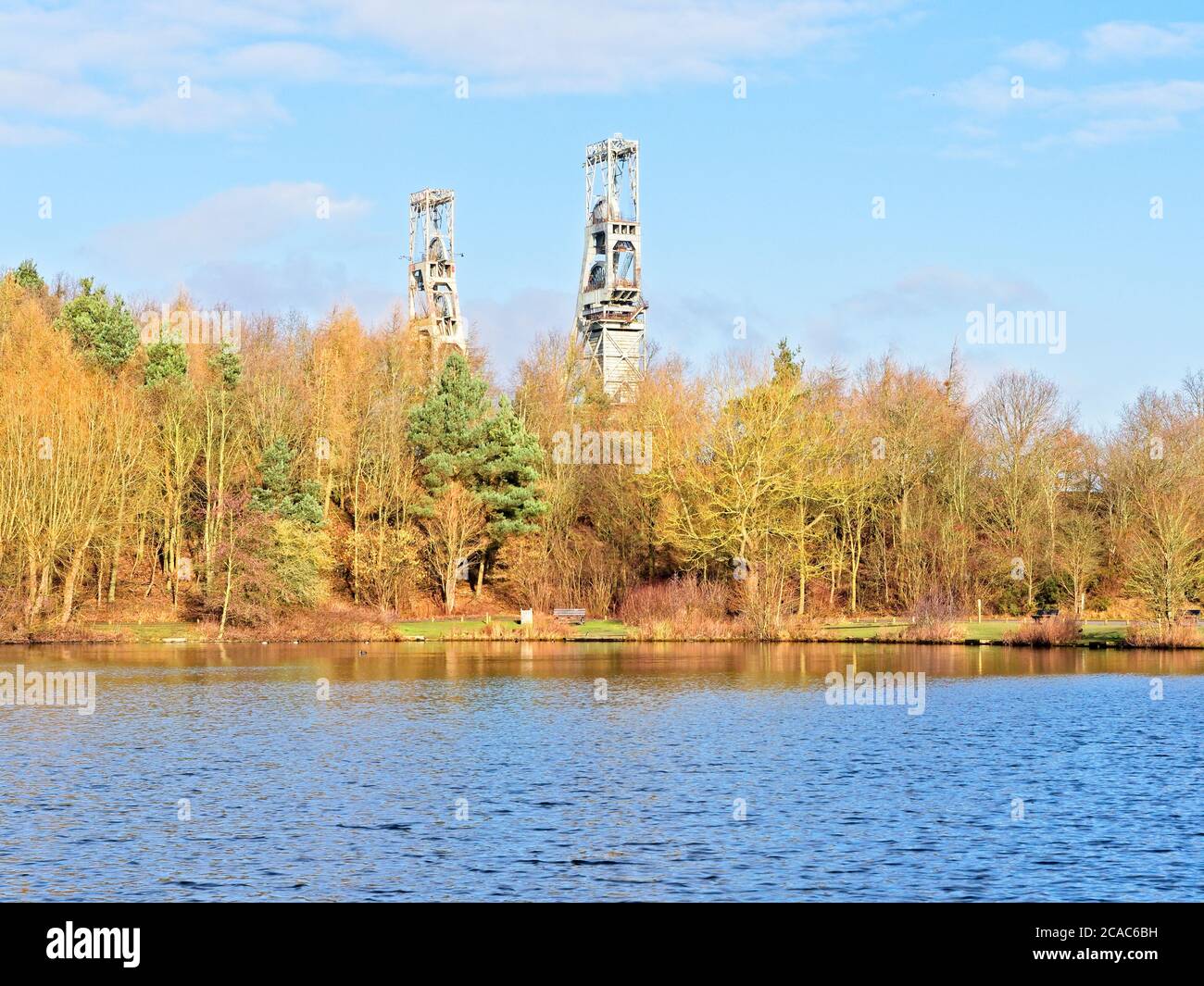 Across the rippled water of Vicar Water lake, partially hidden by dense ...