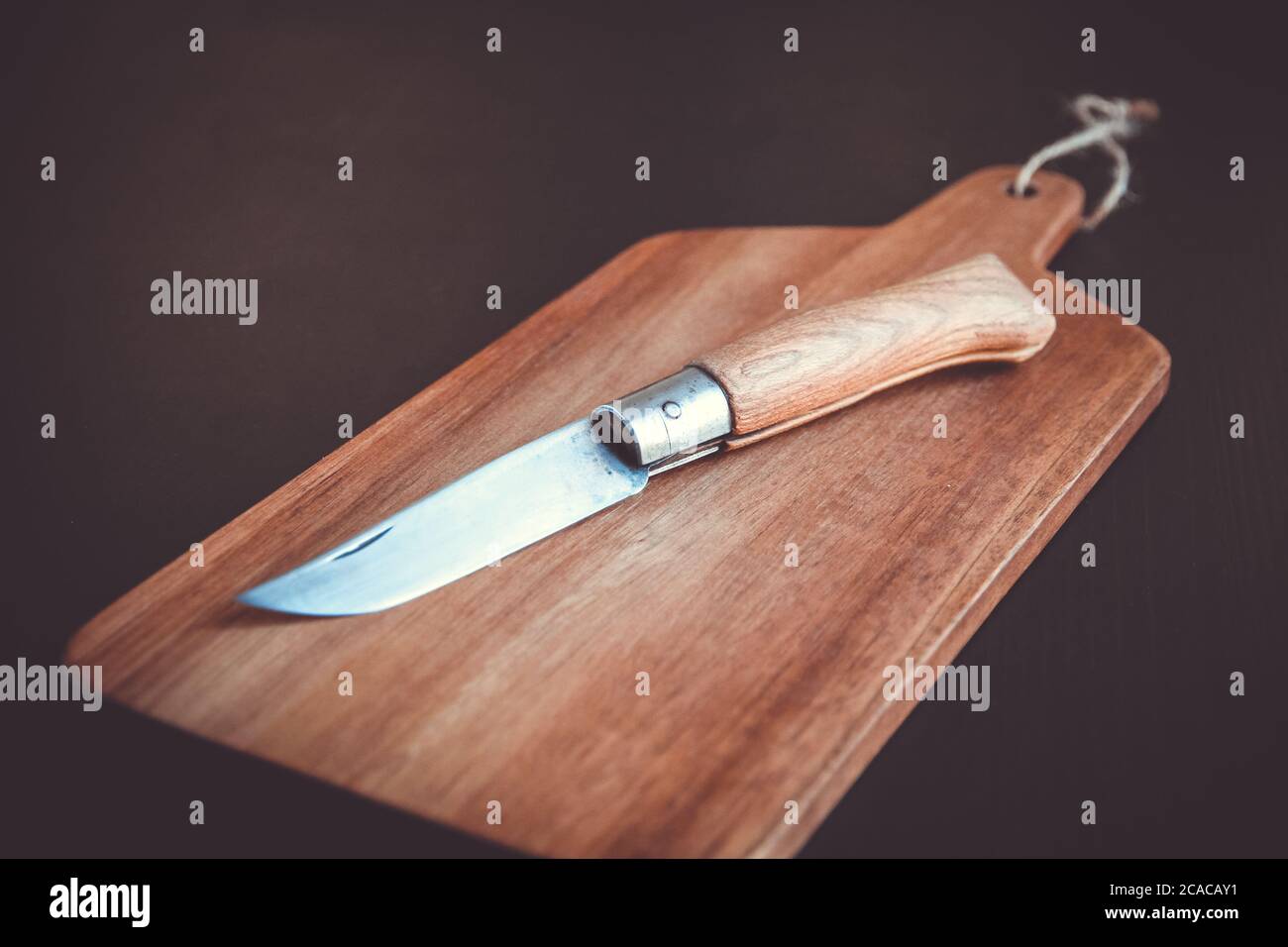 Wooden cutting board and pocket knife on a black kitchen table Stock ...