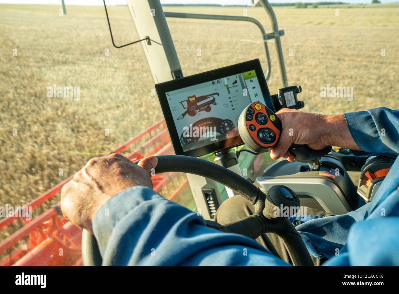 the machine operator at the helm of a modern combine harvester harvests ...