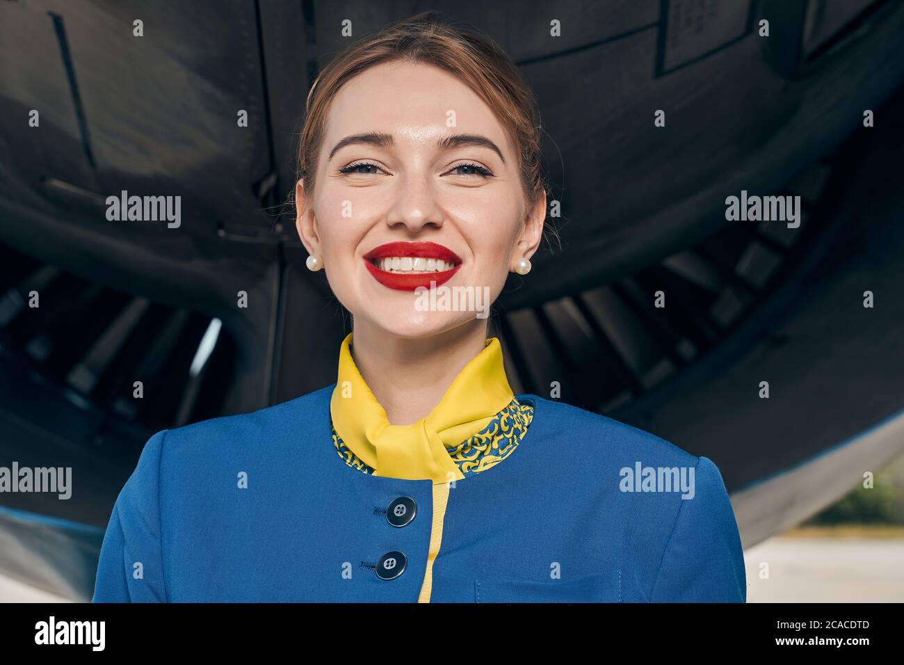 Lovely merry flight attendant standing under the jet engine Stock Photo ...