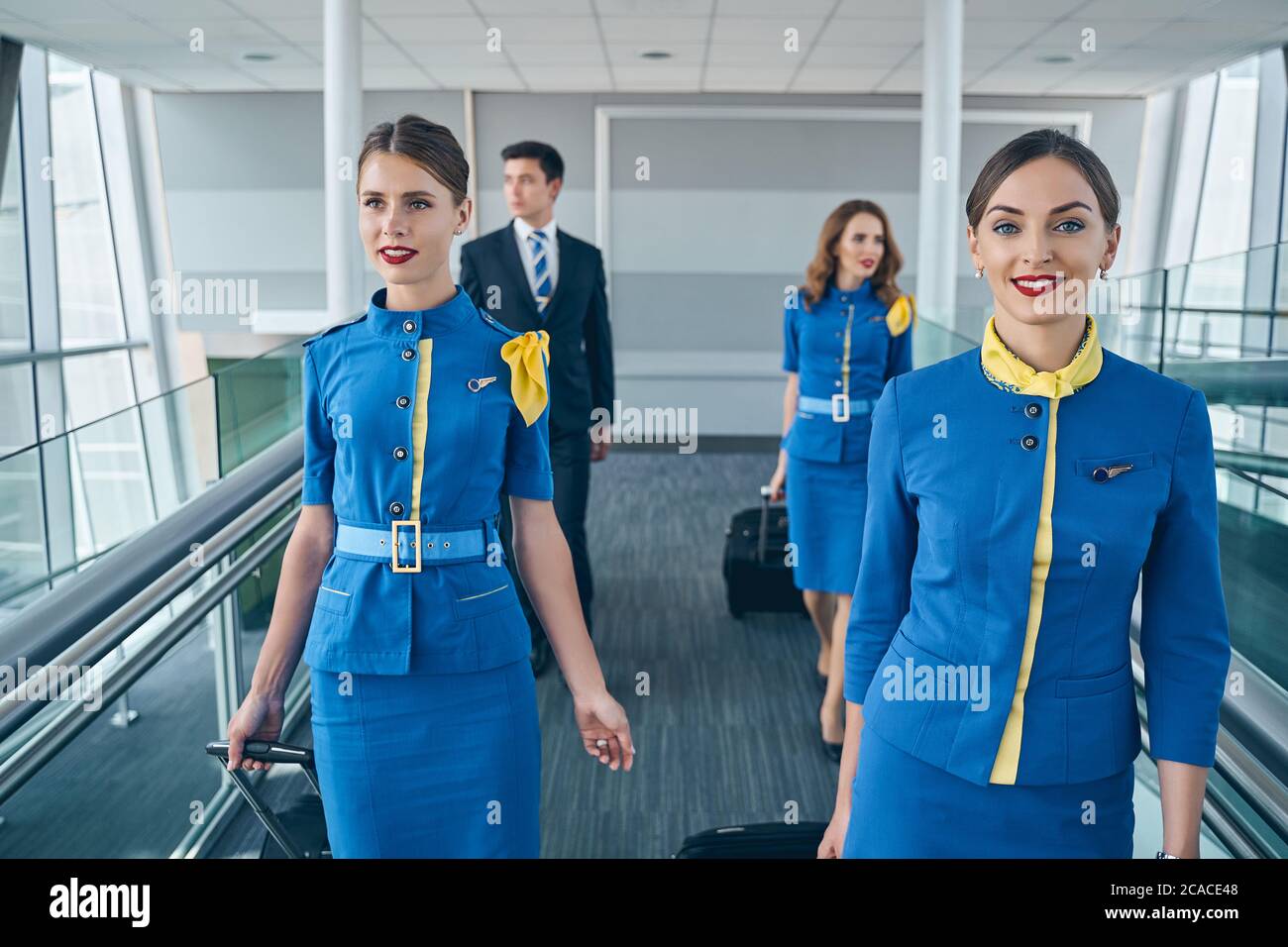 Young airline employees walking along the airport terminal Stock Photo ...