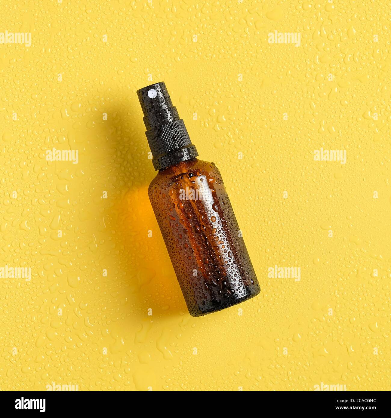 Summer sunscreen lotion bottle in droplets of water on yellow ...