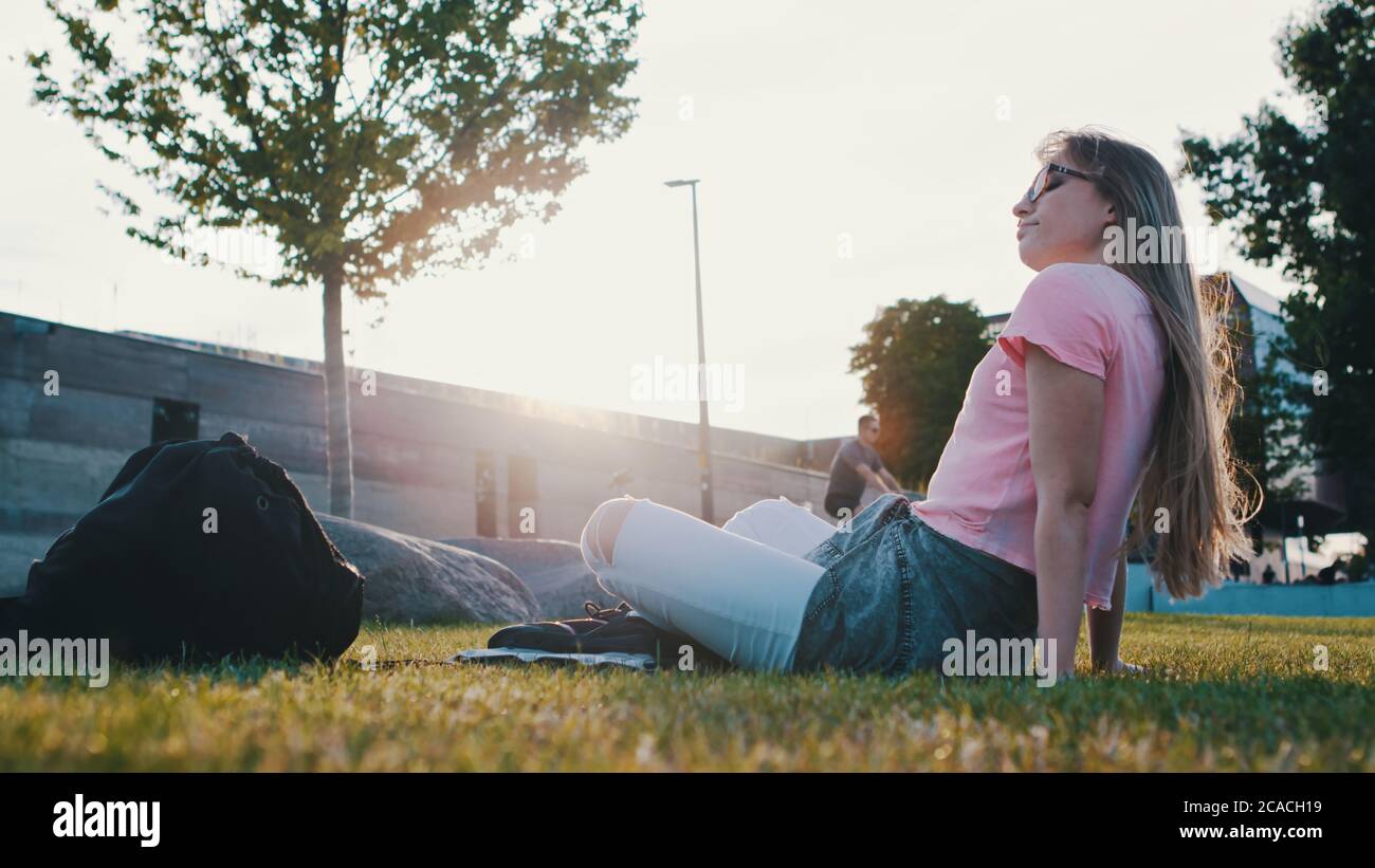Beautiful student relaxing in the park, meditating on the grass. High ...